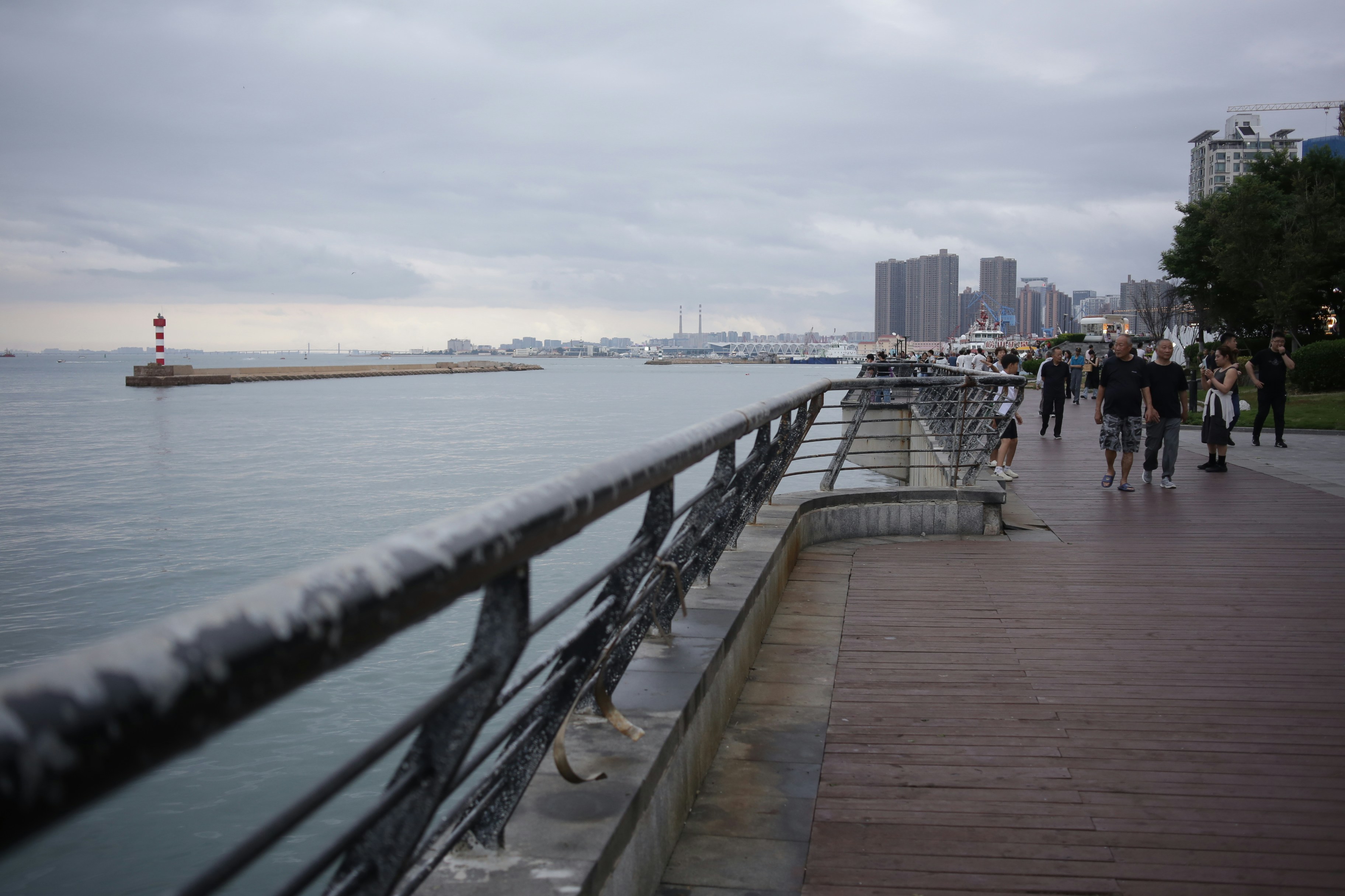 Riverside Promenade with Silhouette of Cityscape and Waterfront Walkers