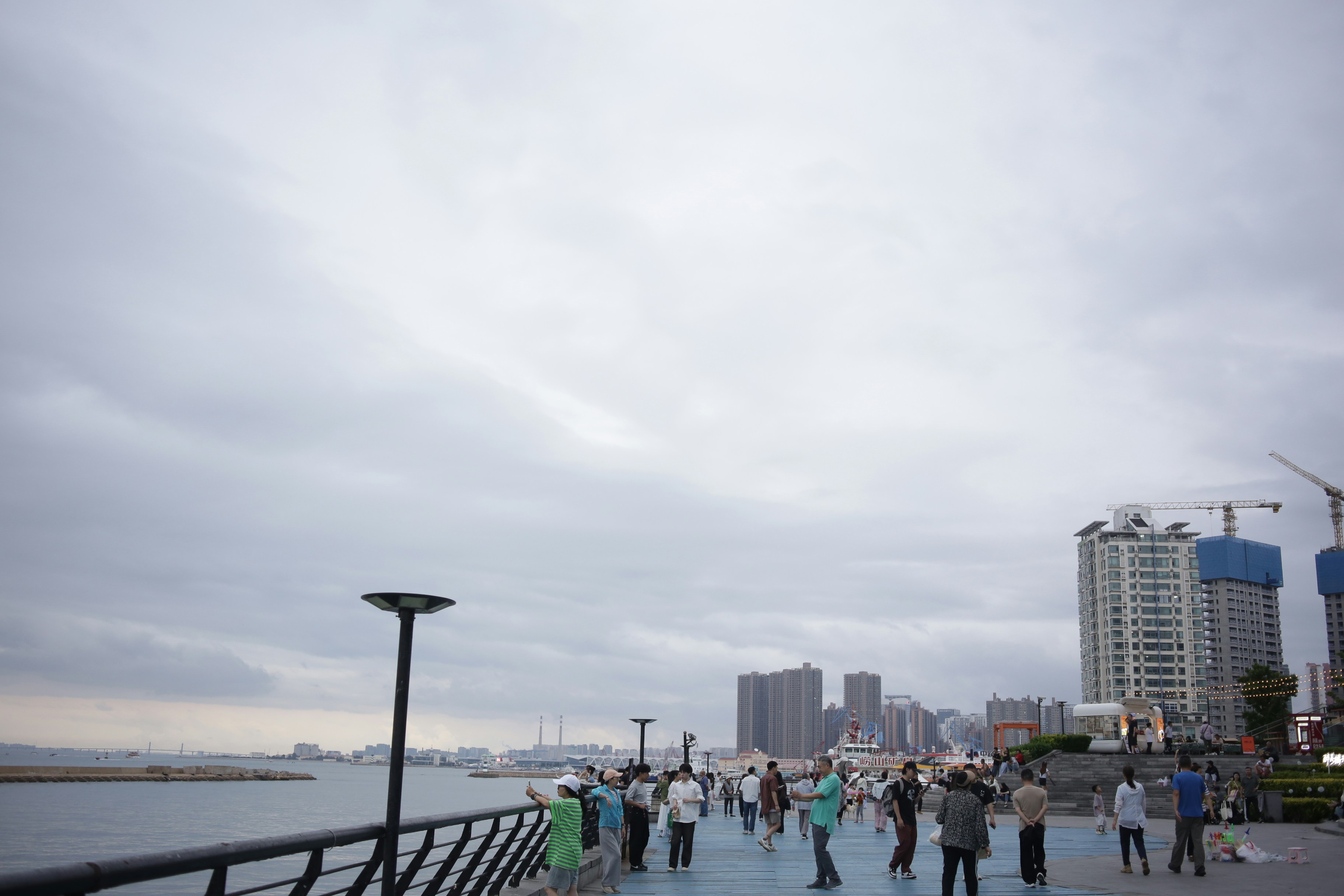 Crowded Promenade by the Harbor at Dusk