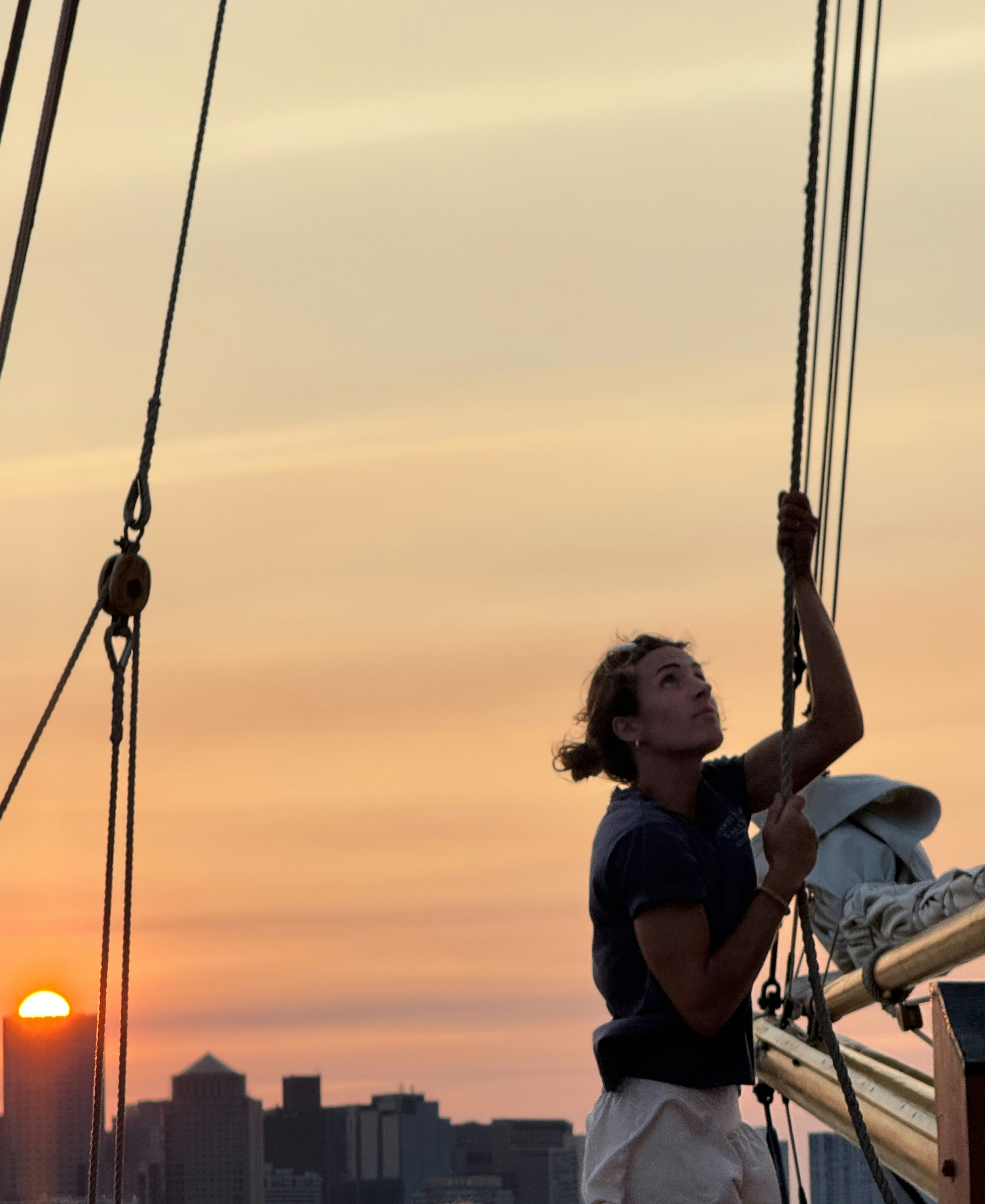 Riser on the Horizon: A Sailor in Quiet Focus Against a Sunset Cityscape