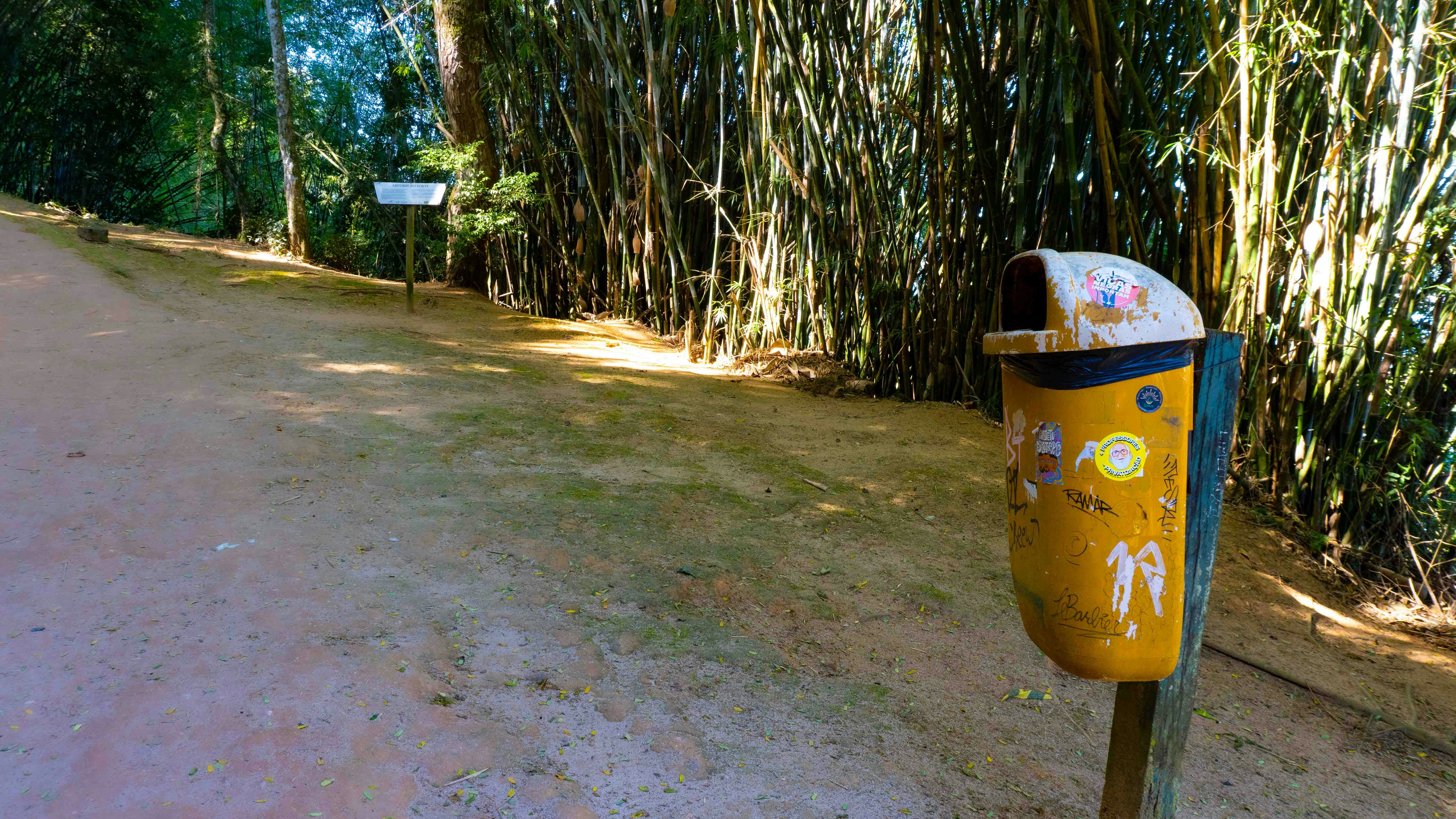 Yellow Public Trash Receptacle in a Shaded Park Path