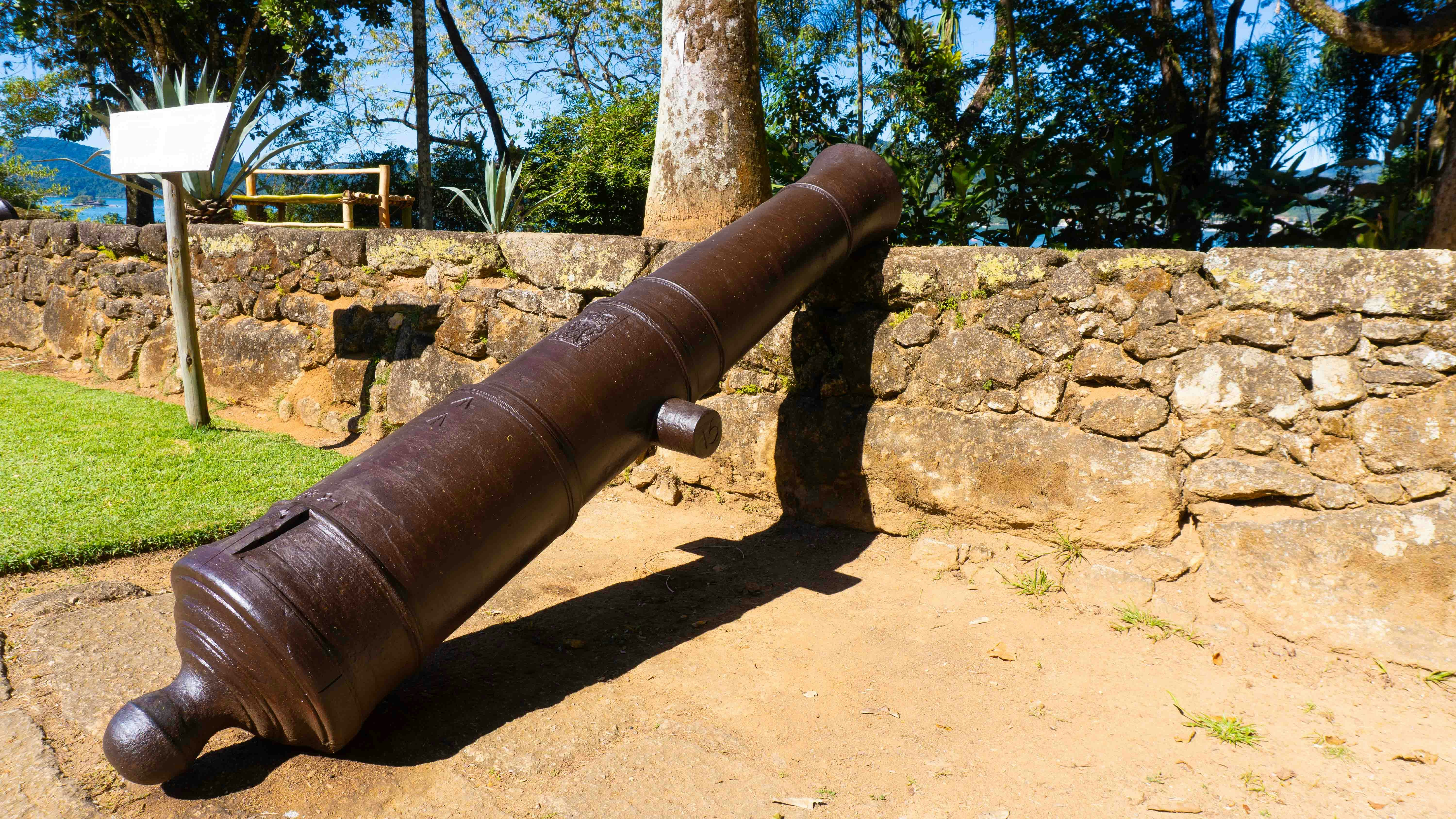 Ancient Harbor Cannon Resting by Sunlit Stone Wall