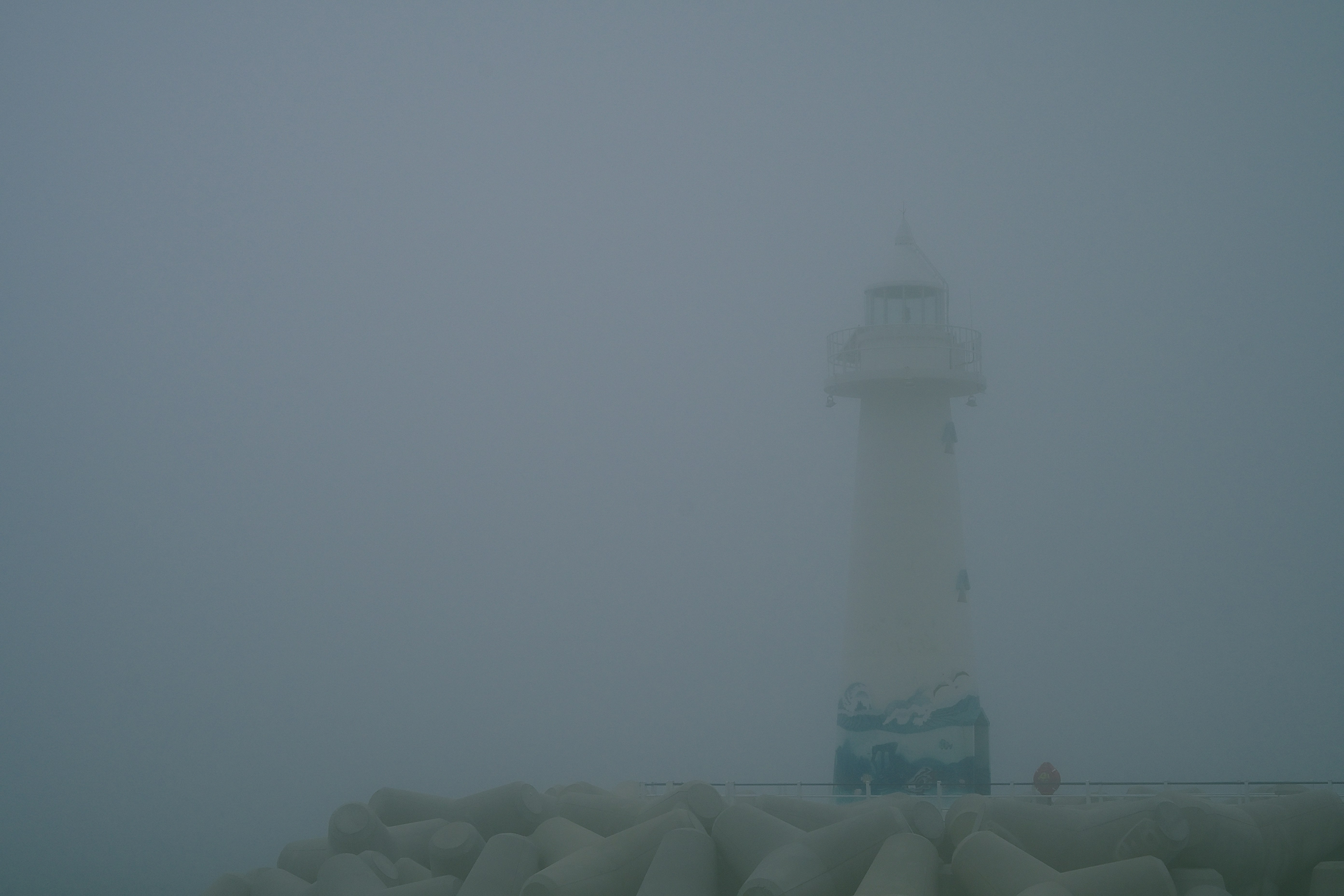 Fogbound Beacon: A Distant Lighthouse Rising Through the Mist