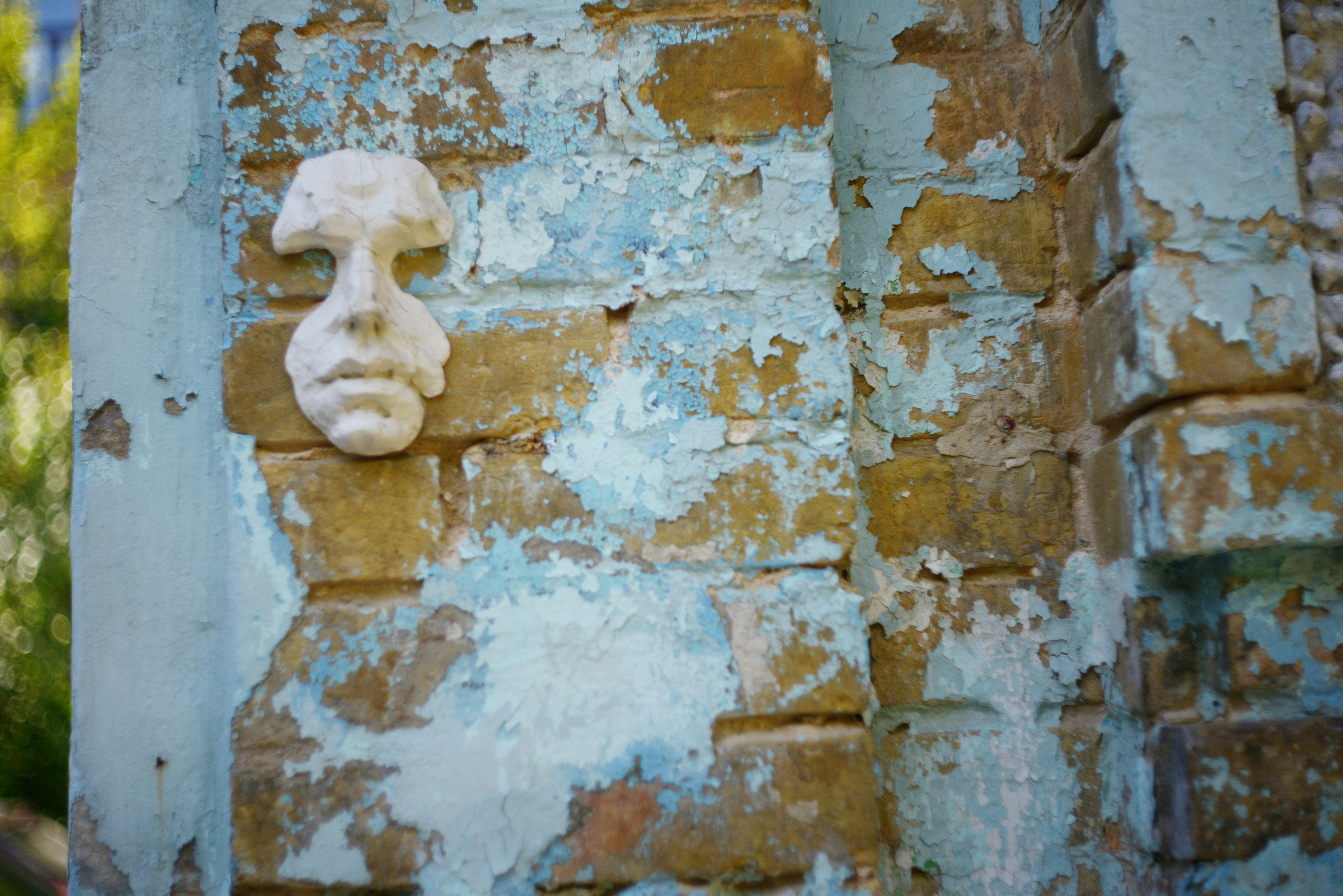 Stone Mask on Weathered Brick: An Abandoned Wall with a Silent Face