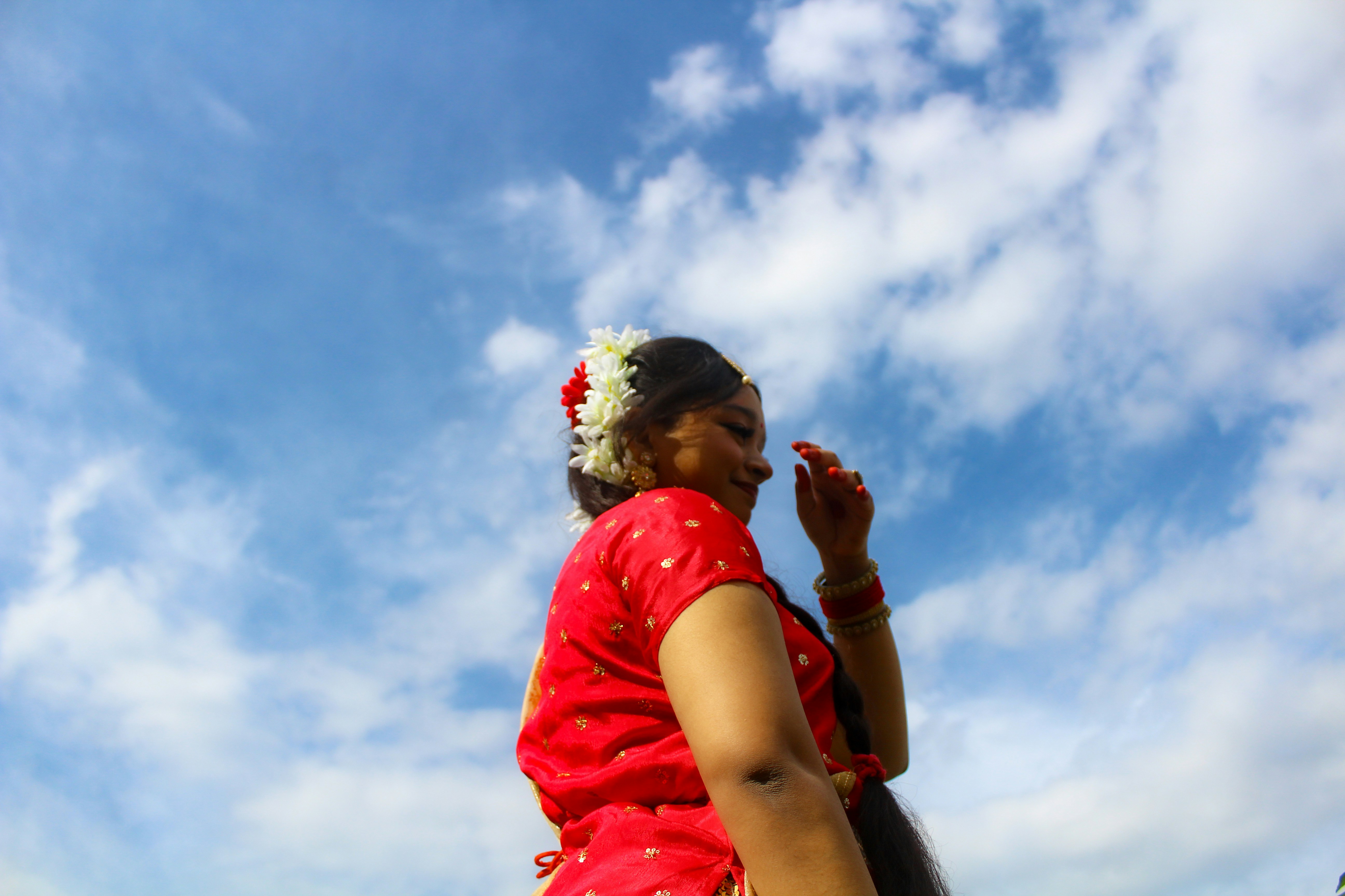 Red-dressed dancer against a bright sky with floral headpiece