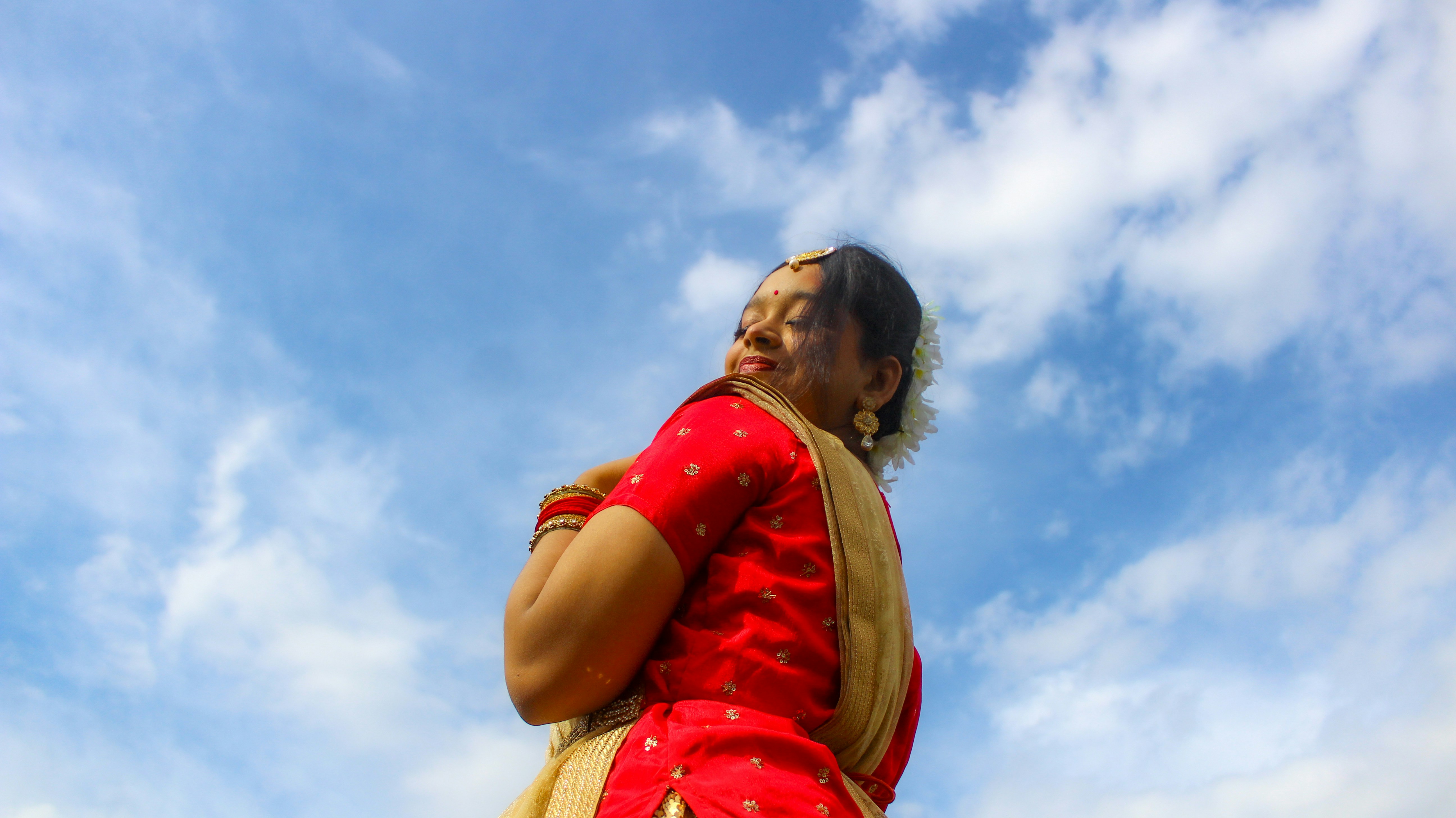 Joyful Pose in a Red Attire Under Broad Sky