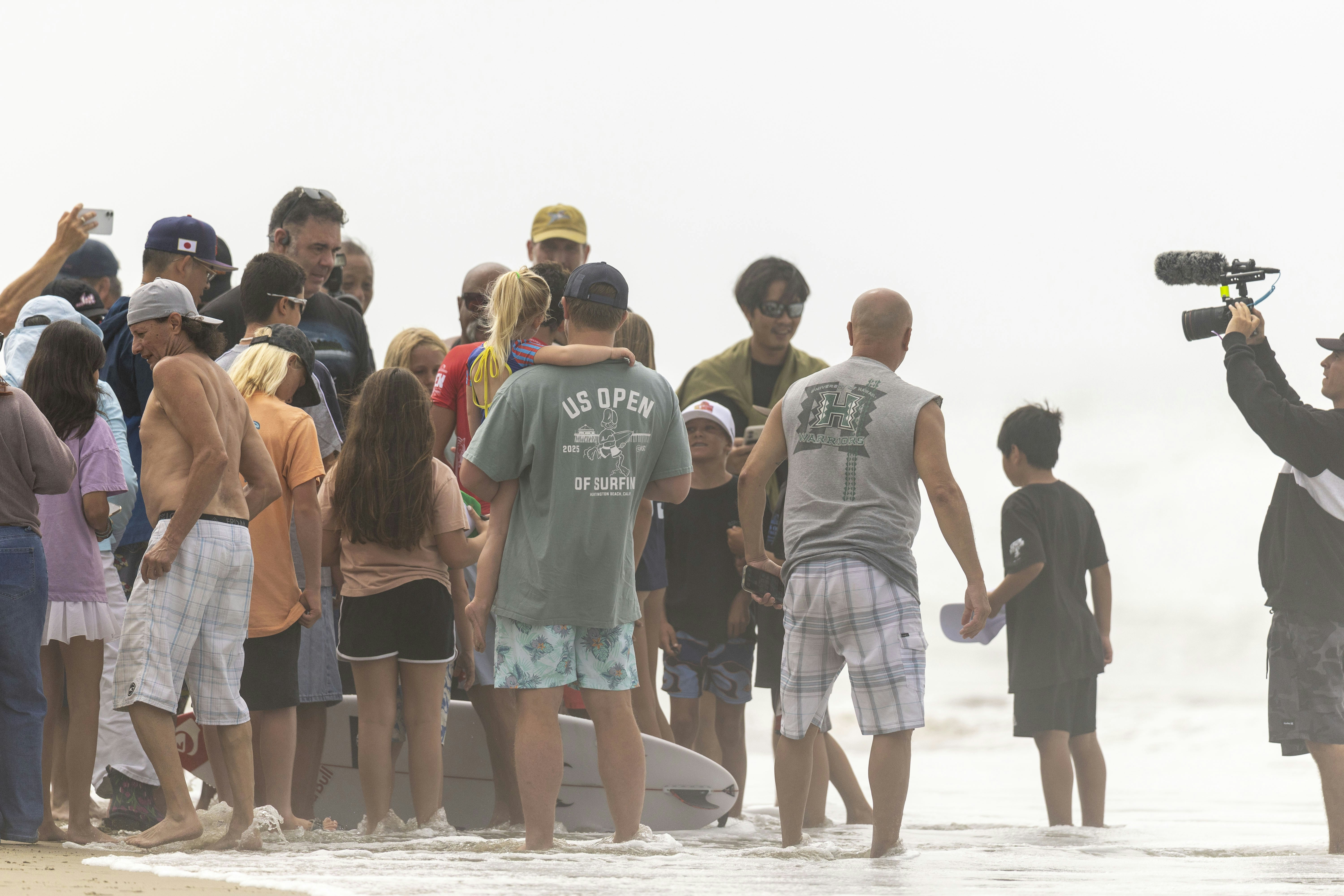 Crowd Gathered at the Shoreline with a Filmmaker Camera on the Right