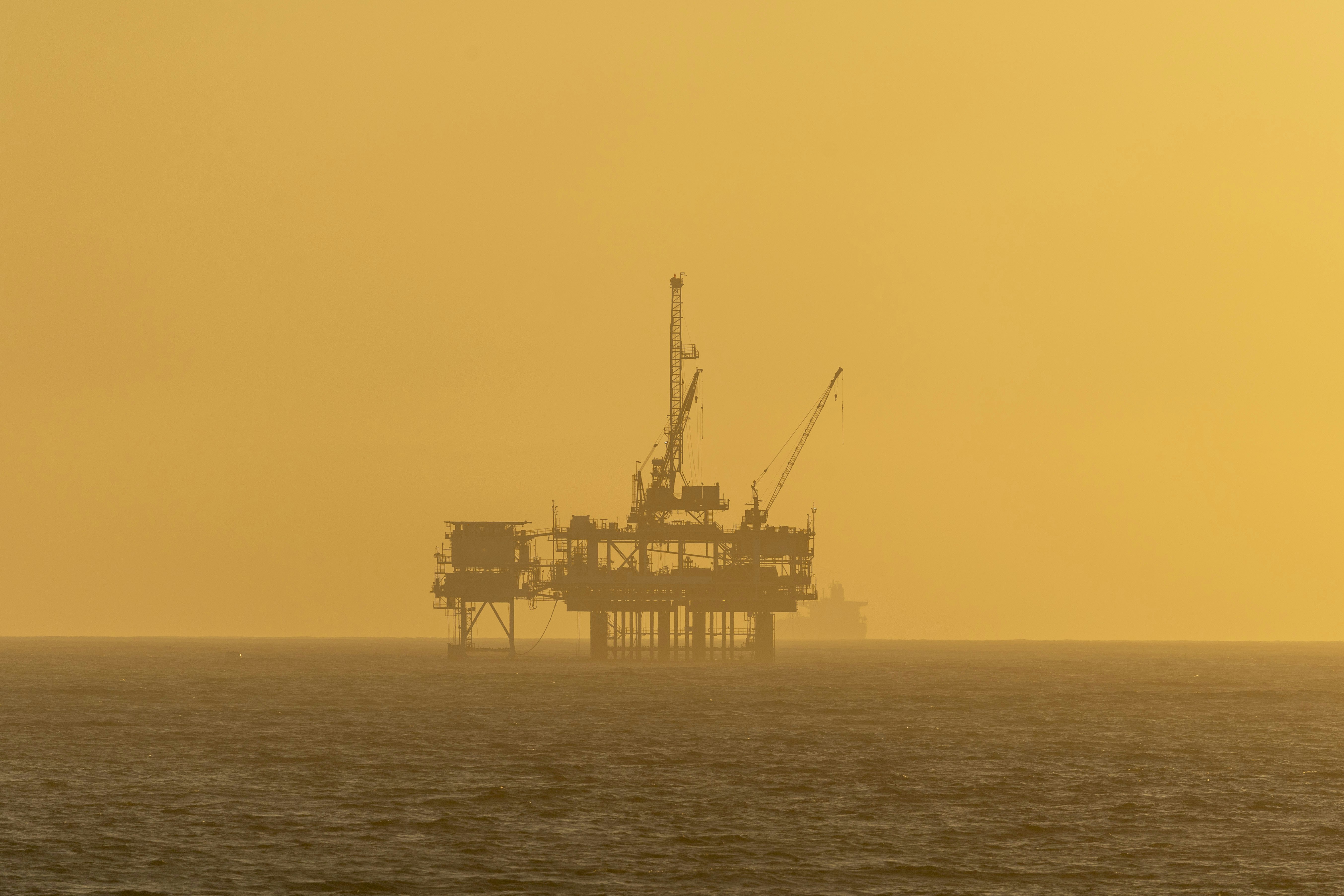 Golden Hour Rig: Offshore Platform Silhouette in Hazy Seas