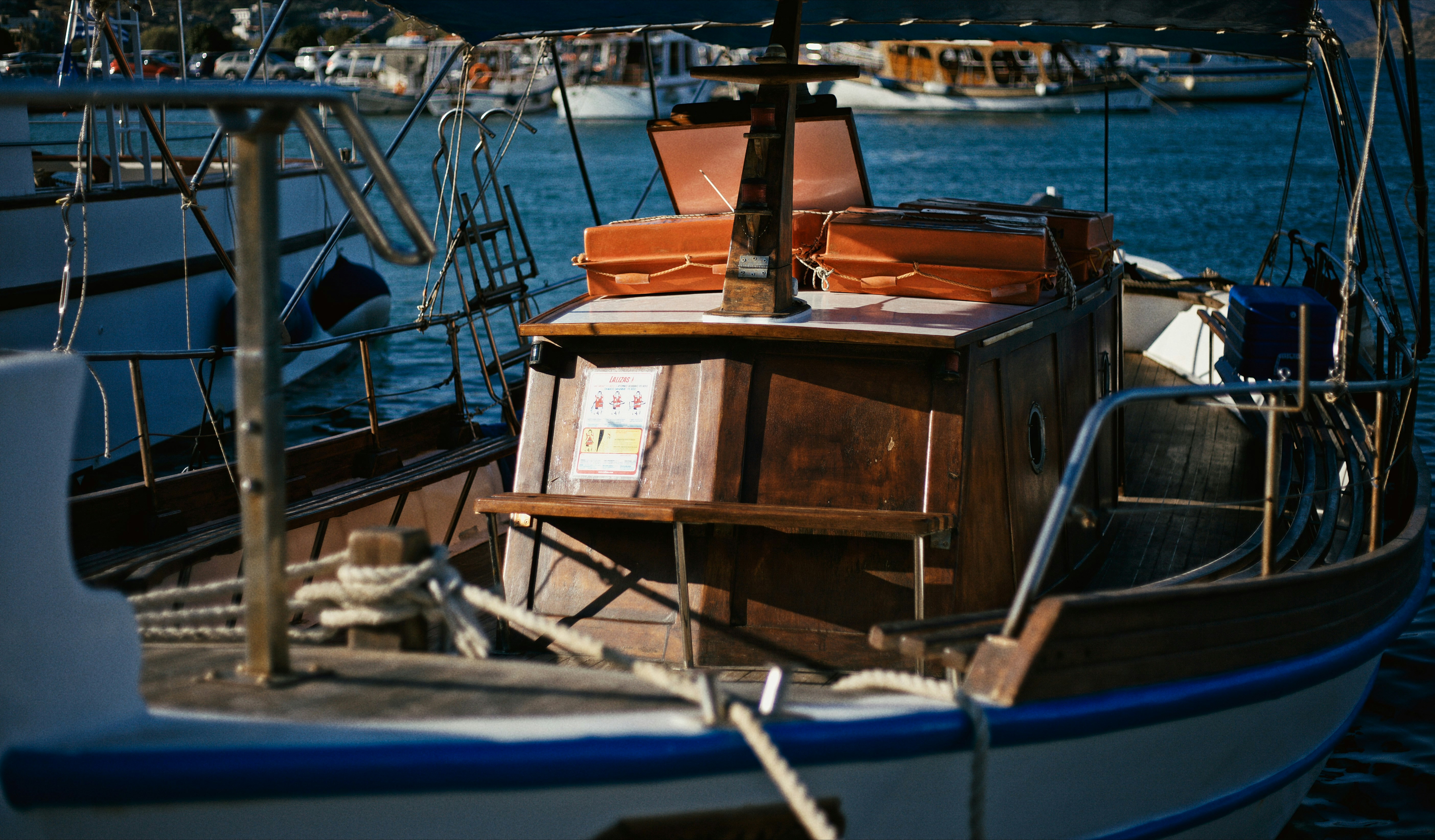 Cockpit of a Quiet Harbor: A Wooden Sailboat Cabin Framed by Blue Hulls