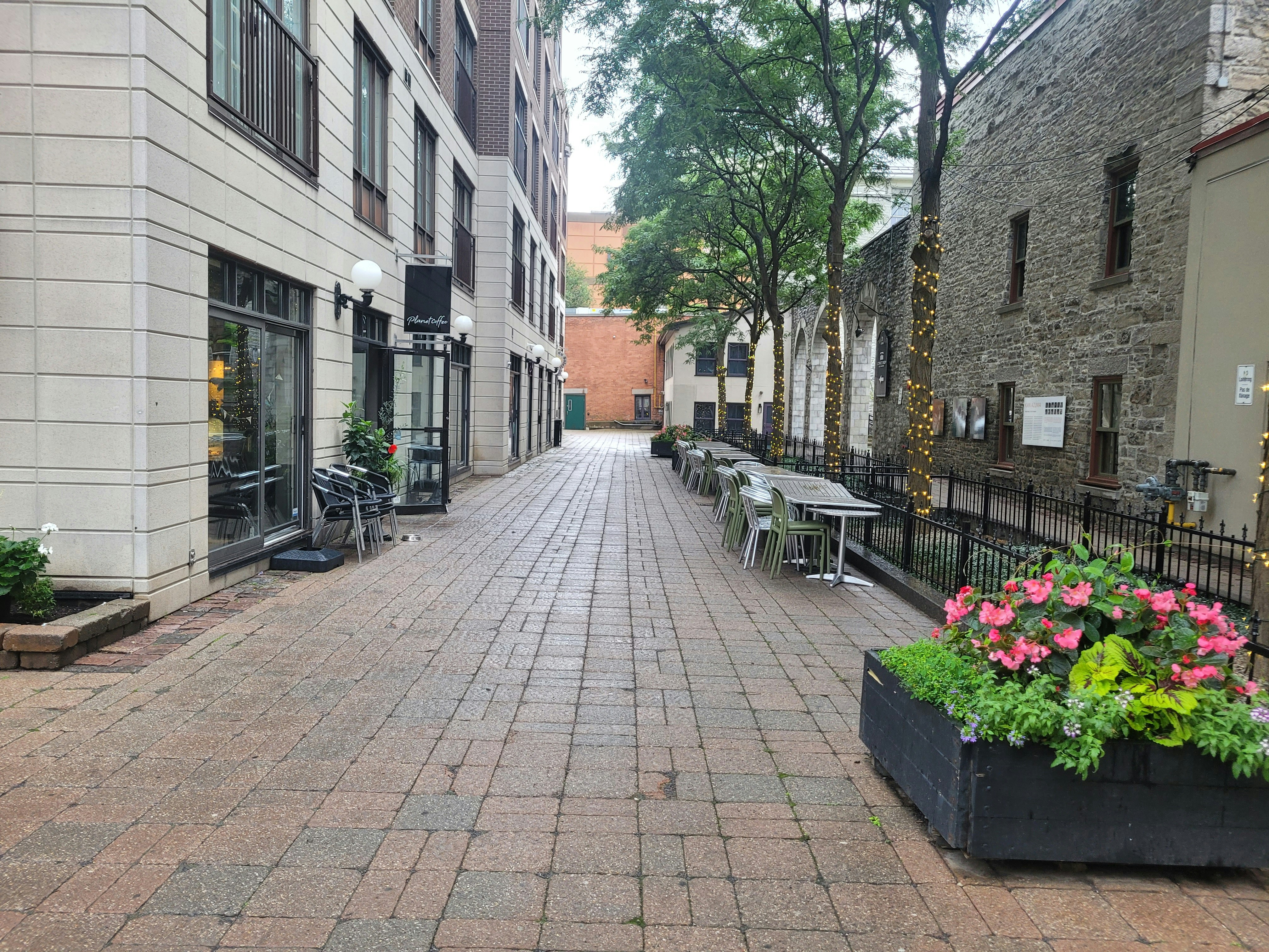 Quiet Urban Corridor: A Row of Outdoor Tables Vanishes into a Brickstreet Alley