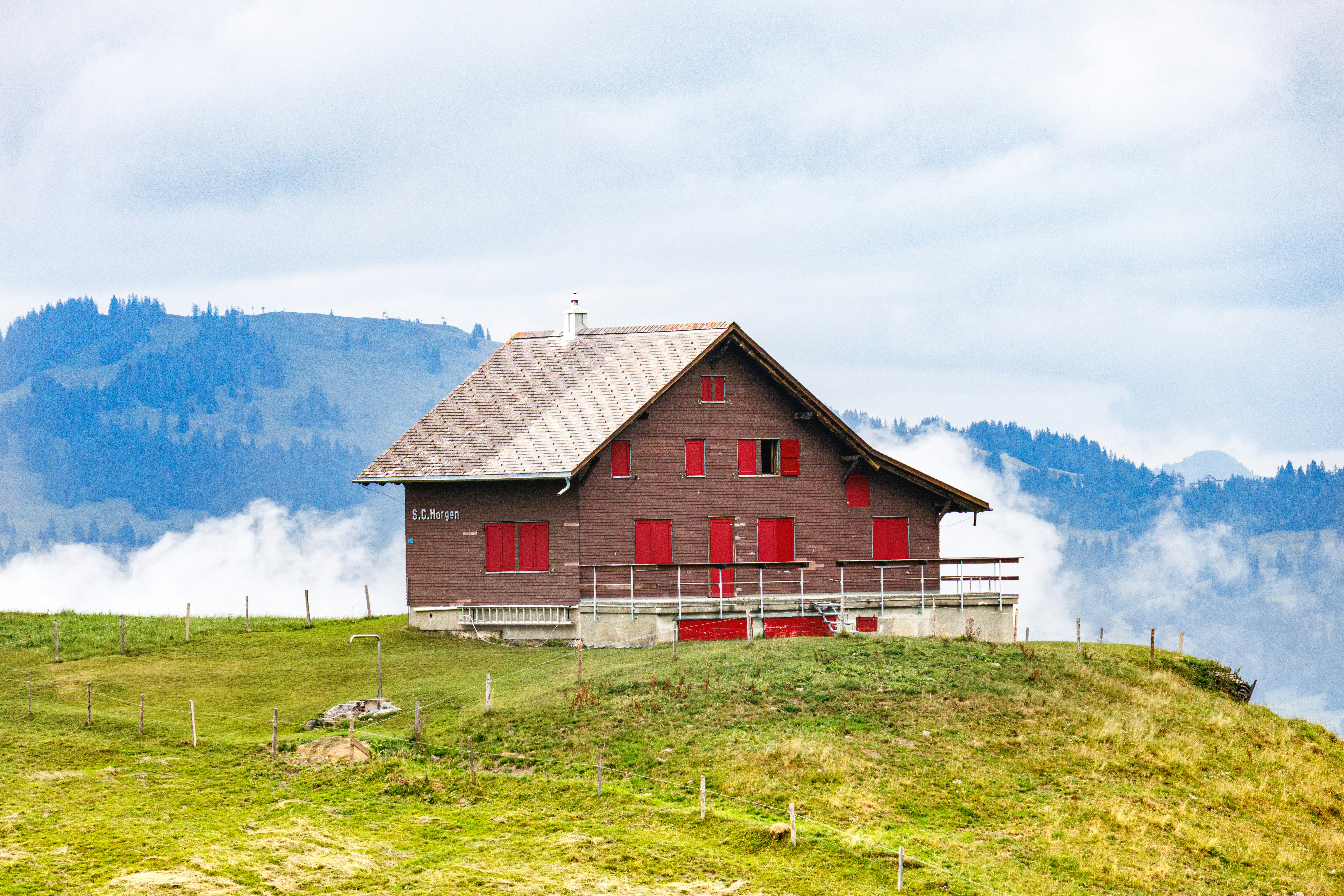 Alpine Refuge: A Red-Windowed Cabin Amid Rolling Pastures