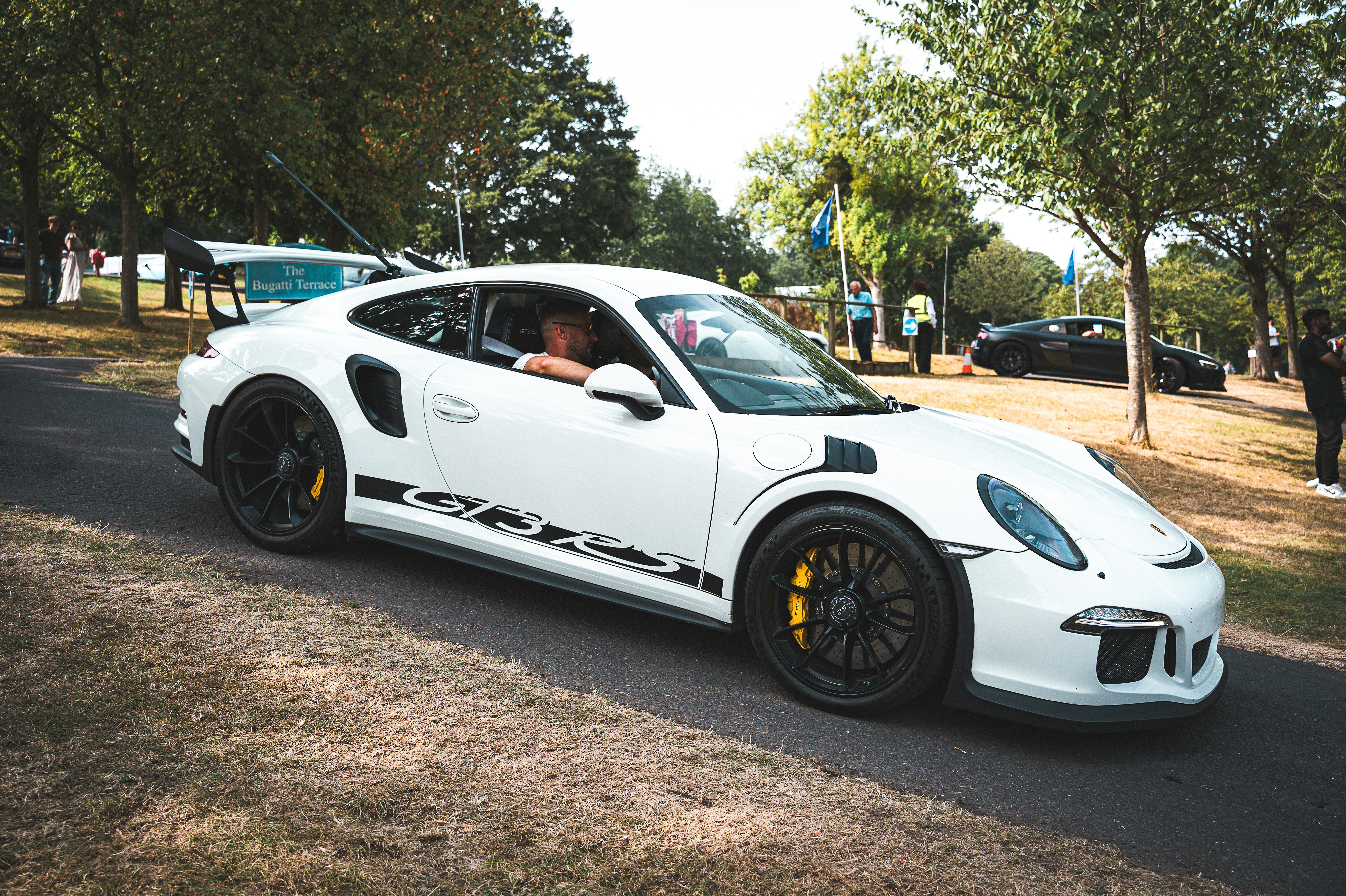 White Porsche 911 GT3 on Display: Side Profile Glow at an Outdoor Car Show