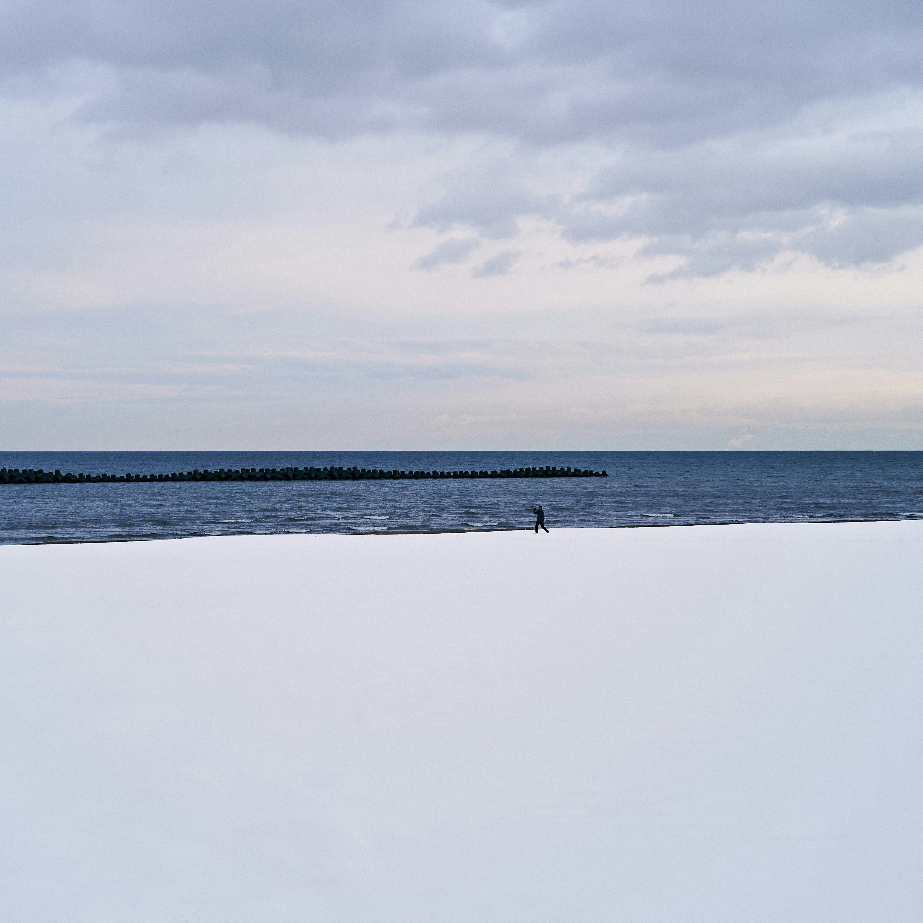 Solitary Runner on a Snow-White Shore under a Choreography of Clouds