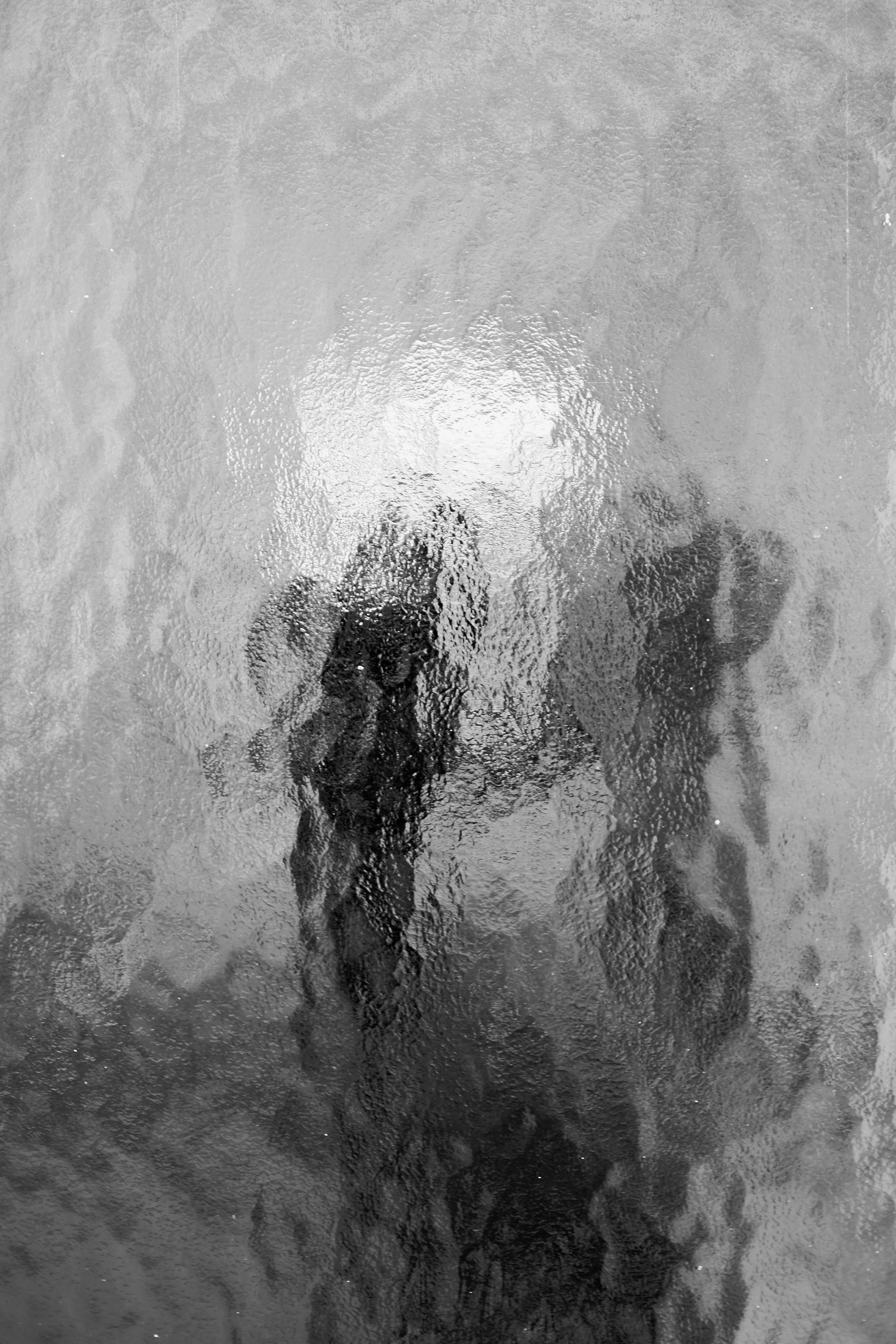 Shrouded Silhouette Behind Textured Glass