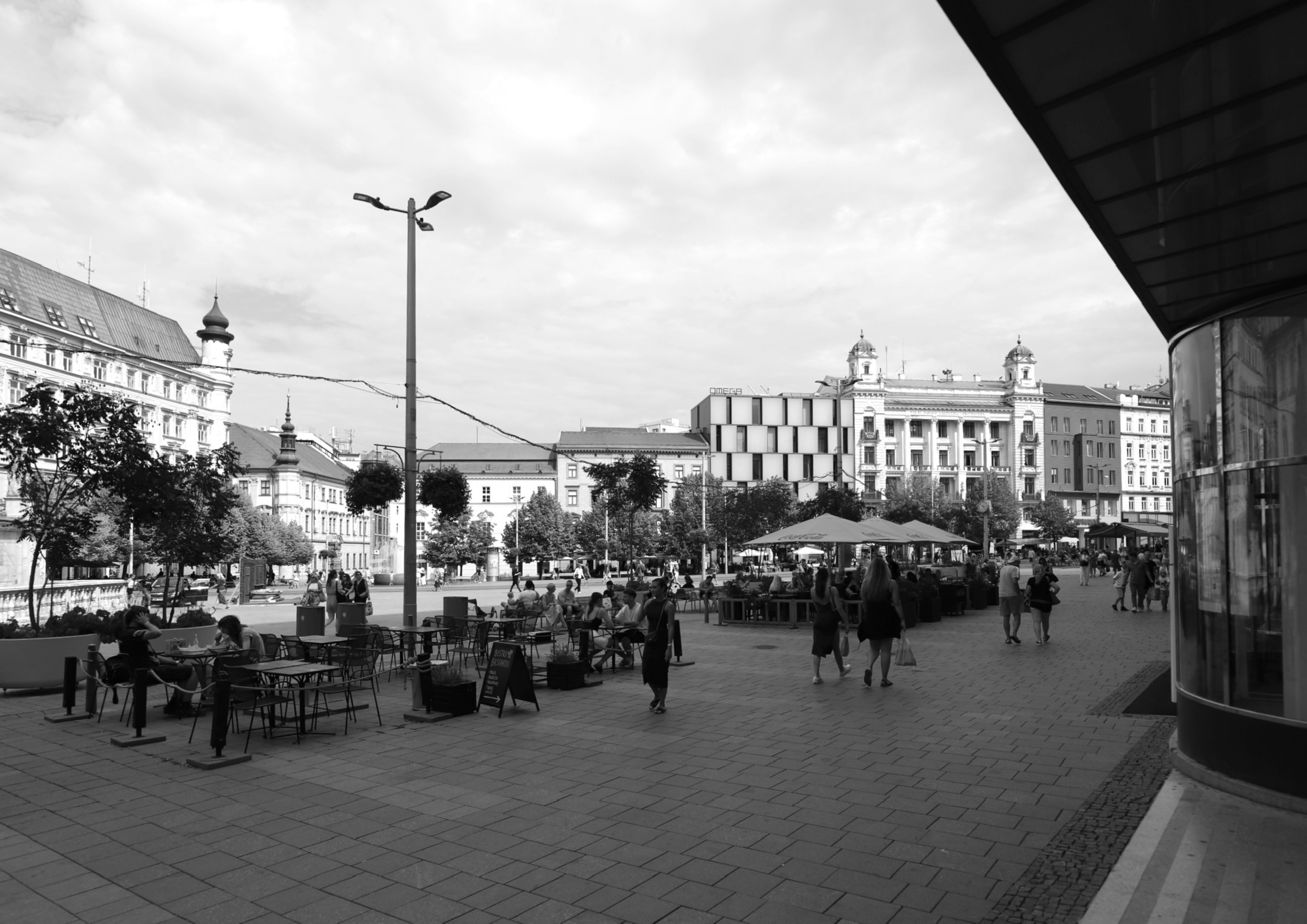 Urban Plaza at Twilight: Quiet Activity Beneath Statues and Street Lamps
