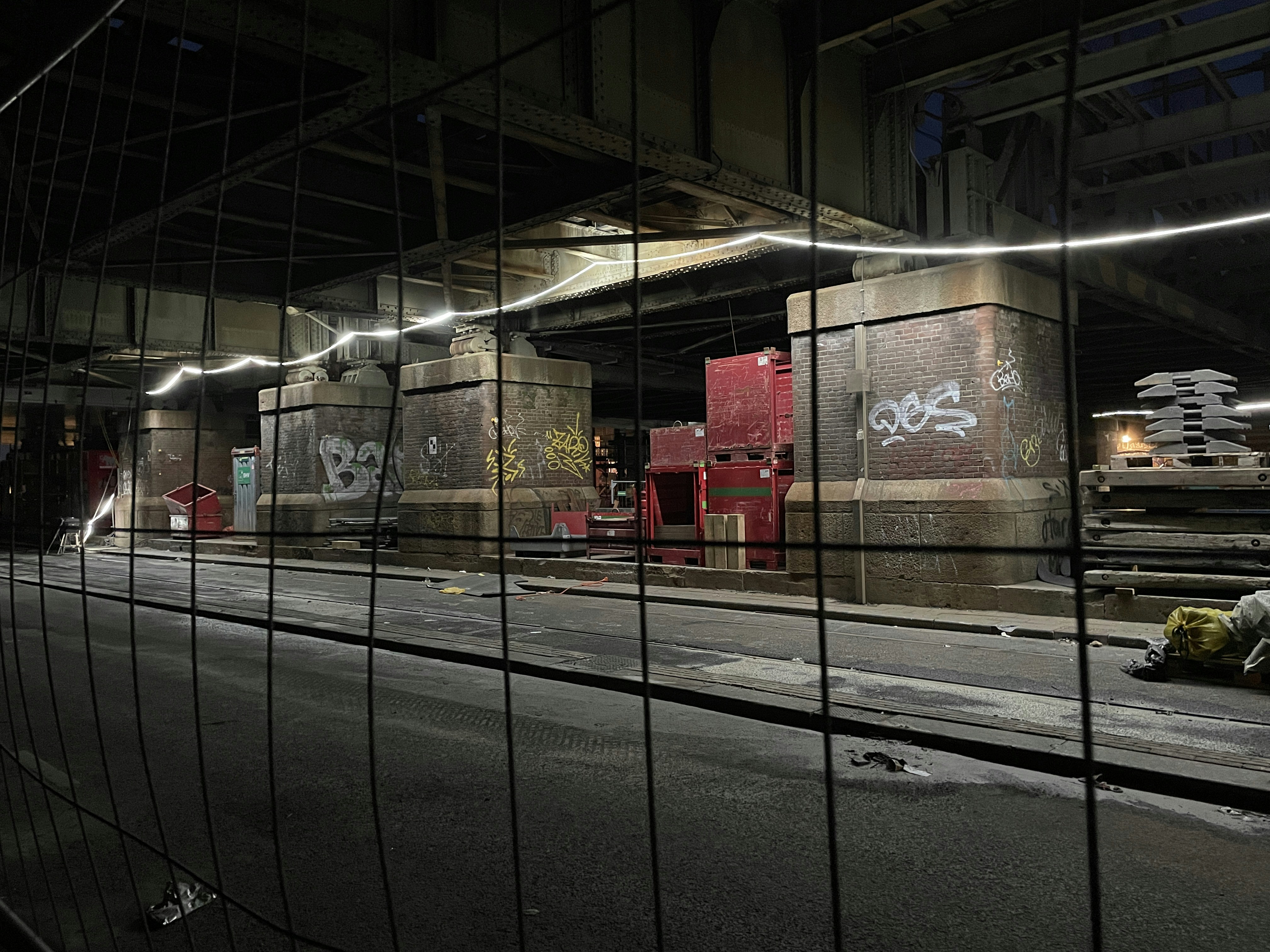 Graffitied Industrial Quiet: Train Yard Under Neon Rods