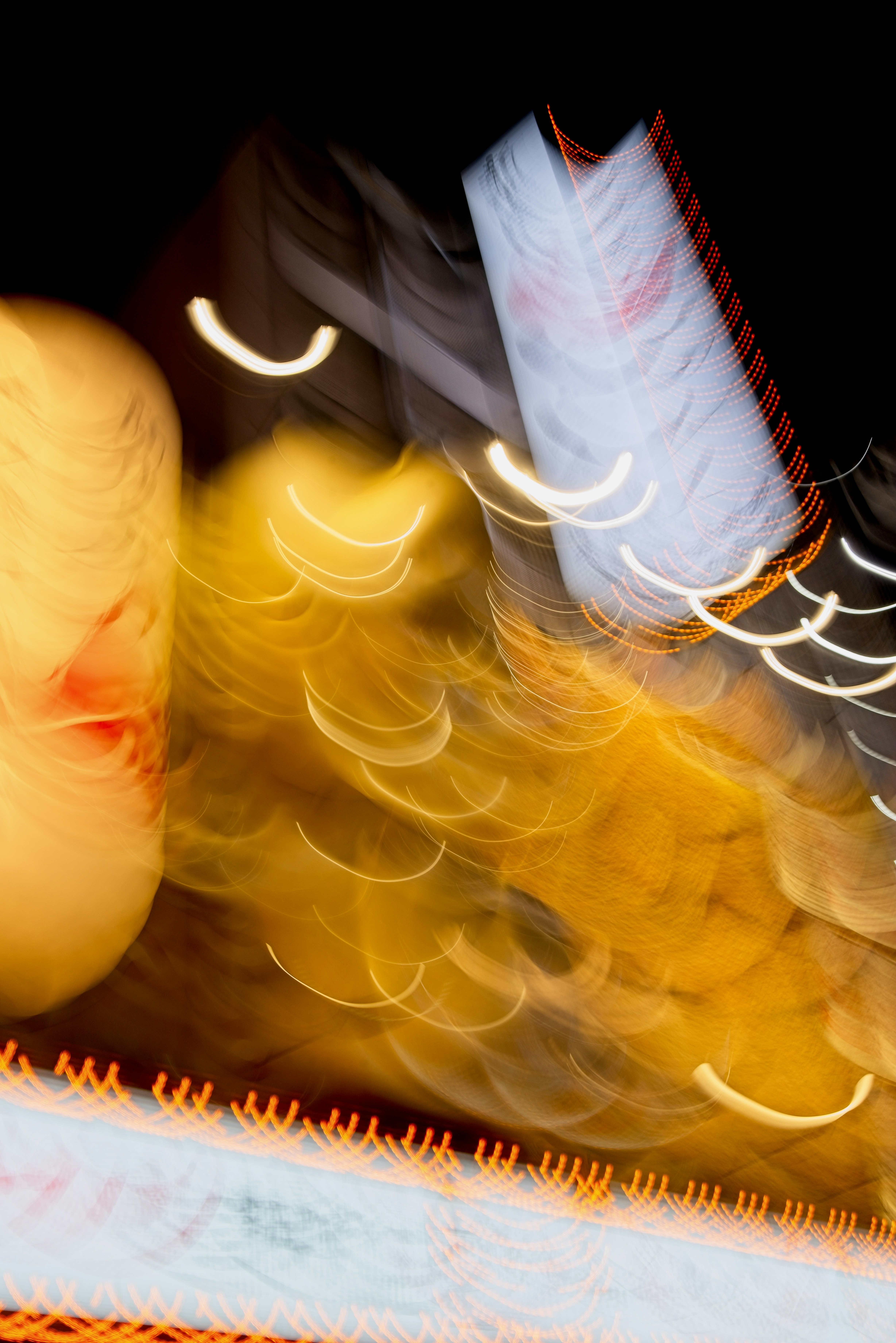 An abstract long-exposure capture transforms the glowing signs and lanterns of Dotonbori in Osaka into a swirling dance of warm orange, yellow, and white light trails on a hot summer evening in July. Deliberate camera movement blurs recognizable shapes into curved streaks and soft arcs, creating a dreamlike, painterly effect. The interplay of golden bokeh and sharp red-orange accents evokes the electric energy of the district's neon-lit streets, offering an artistic, impressionistic interpretation of Osaka's iconic nighttime glow.