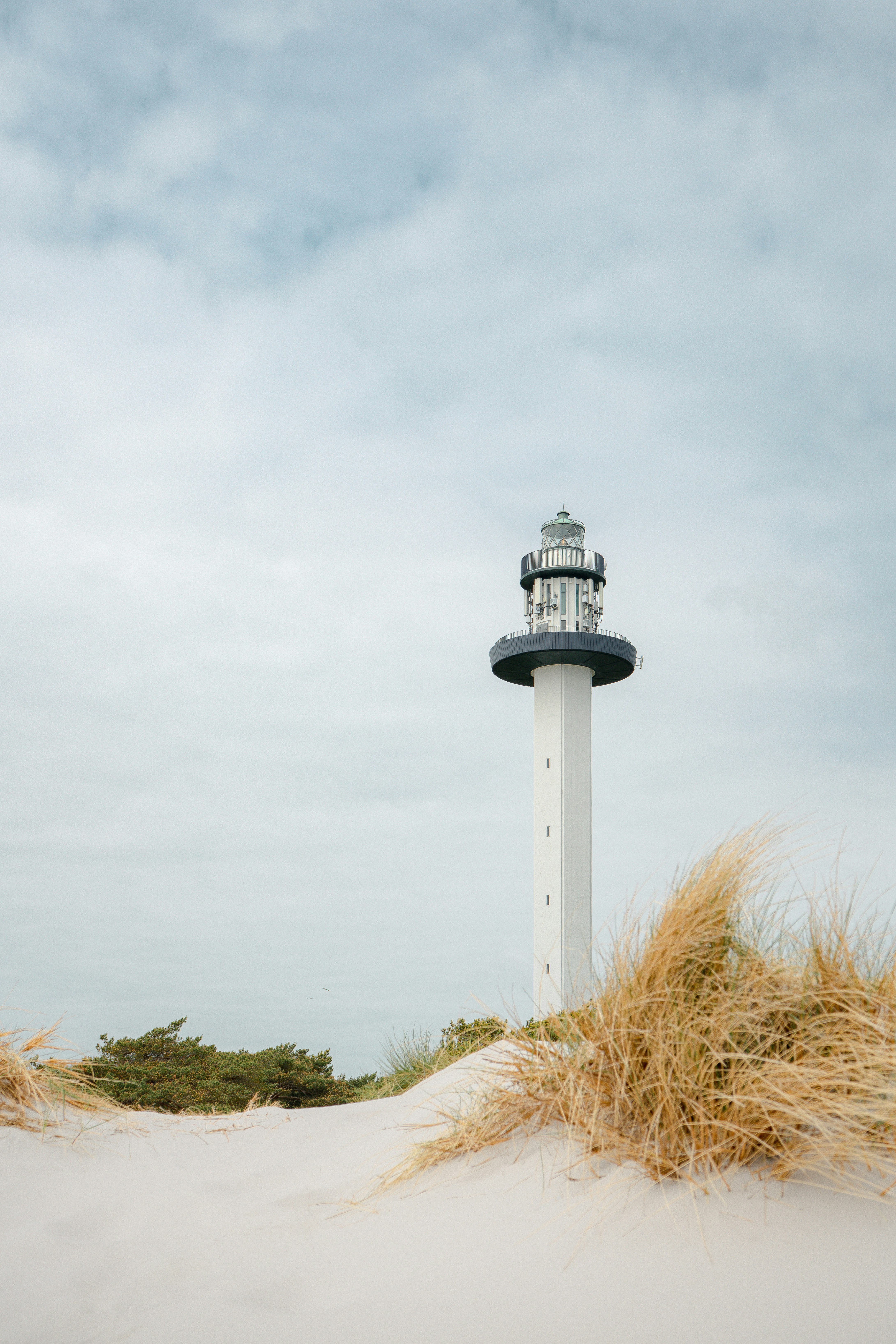 Lighthouse over coastal dunes under a pale sky