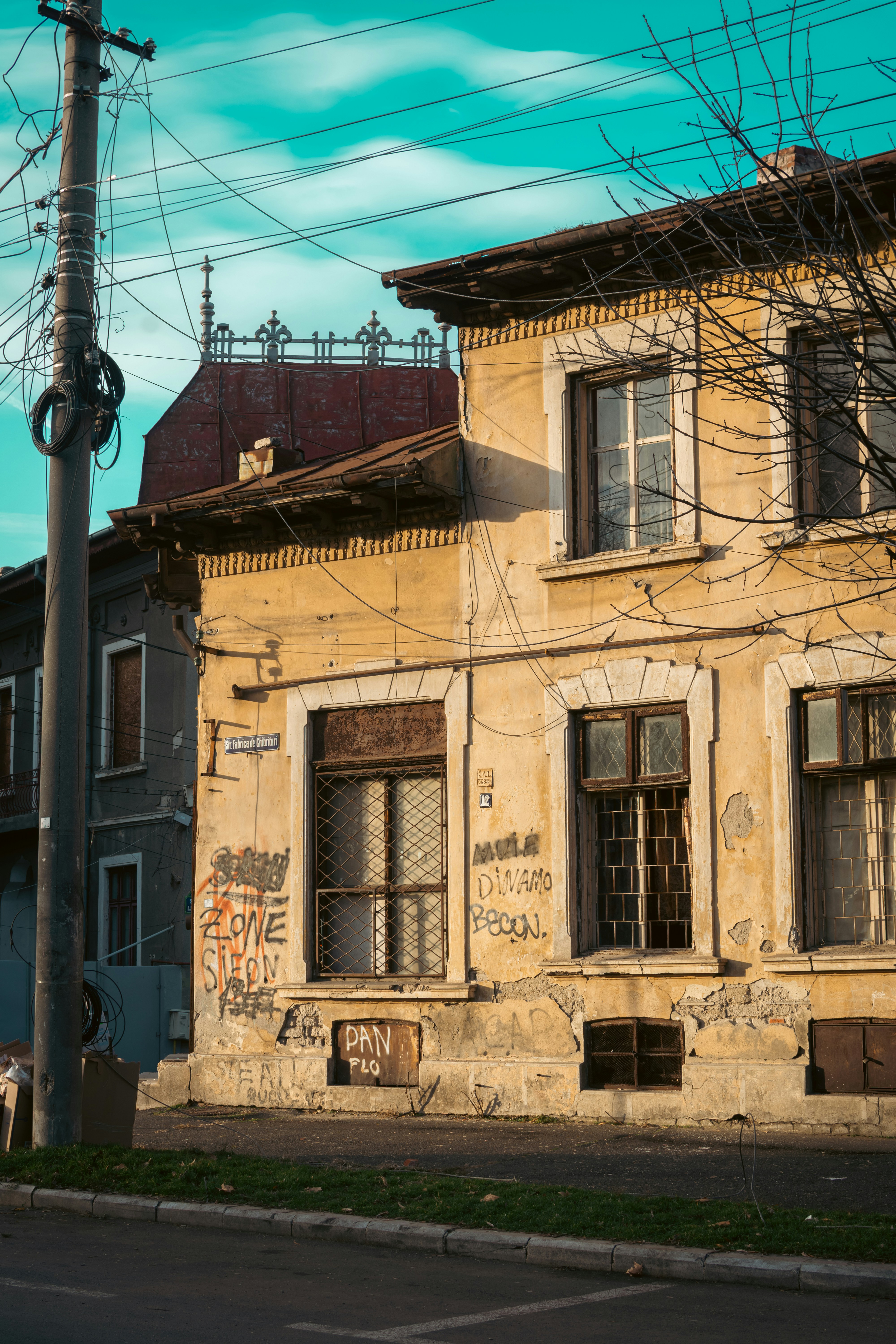 Sunlit Yellow Facade with Graffiti and Weathered Windows