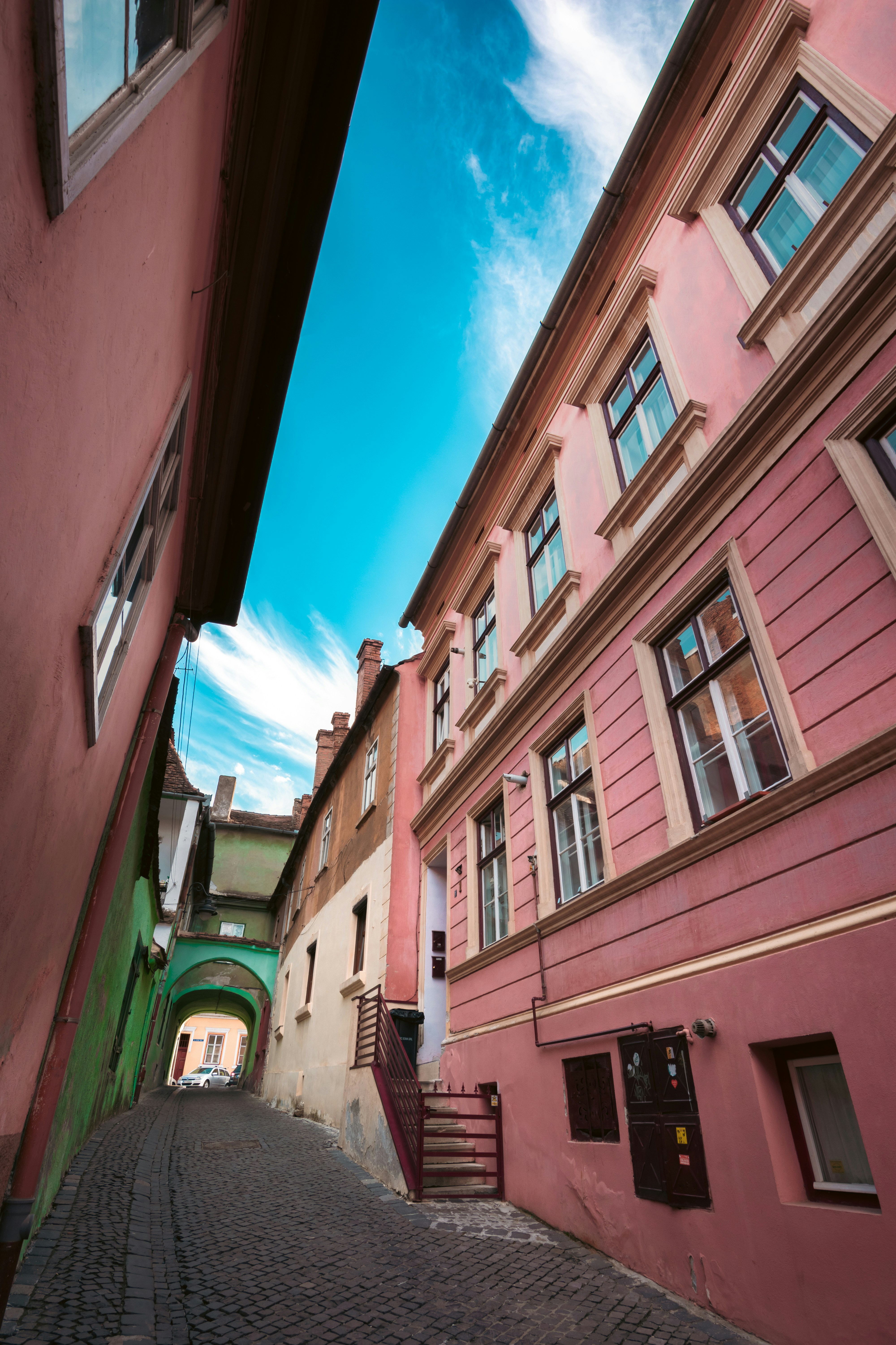 Pastel alleyway converging toward a sunlit arch