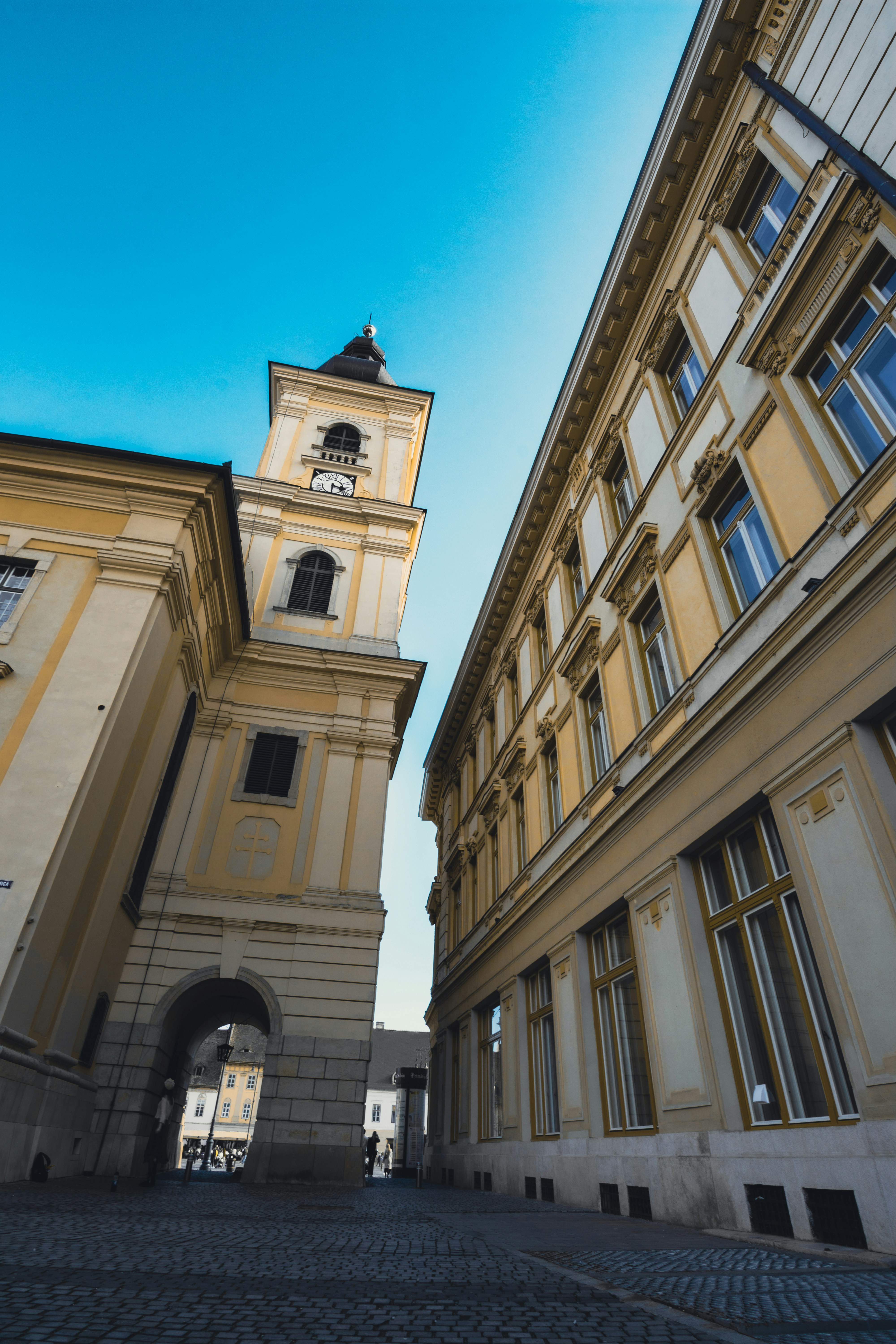 Through the Arch: A Narrow View of Warm Facades and Sky