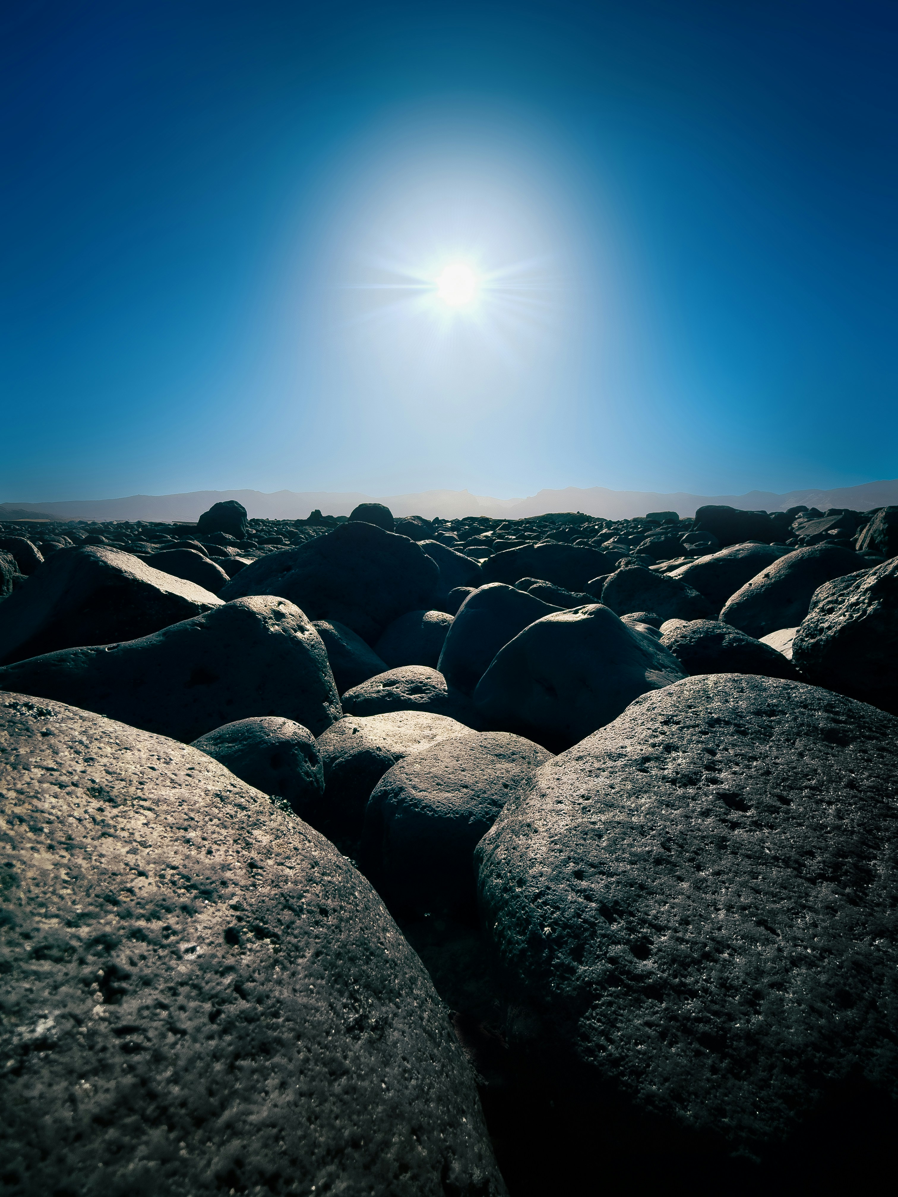 Field of Moon-Rounded Boulders Under a Pale Sun