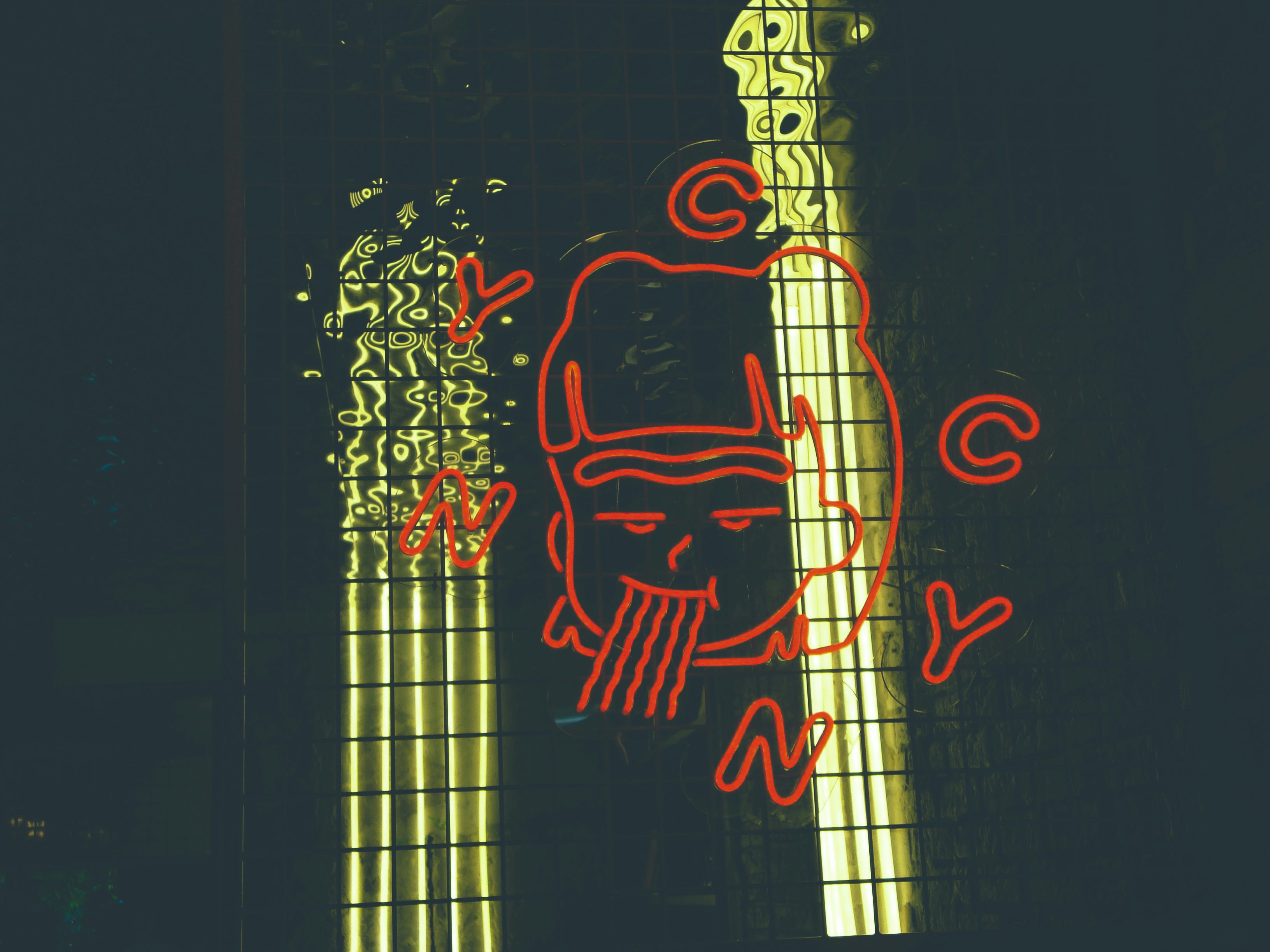 Neon Graffiti cat with open mouth on a dark storefront
