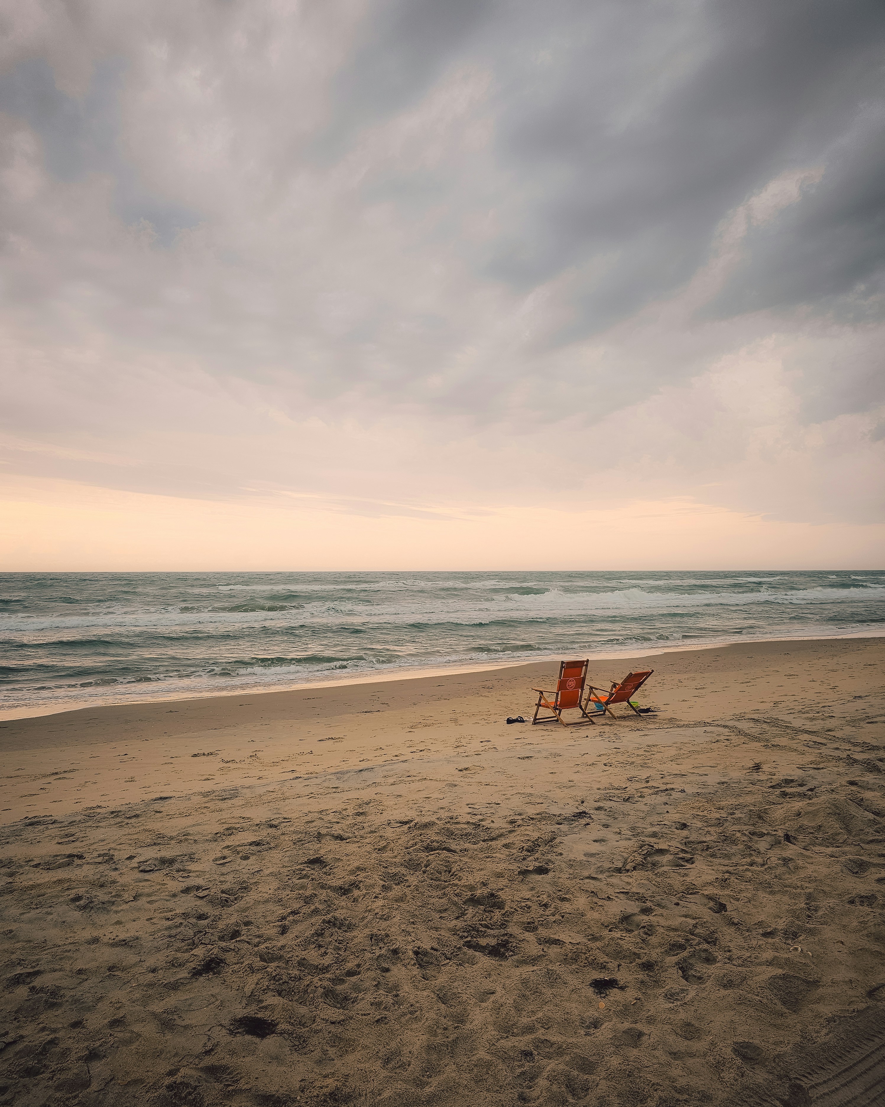 Quiet Shoreline Sunset with Weathered Chairs