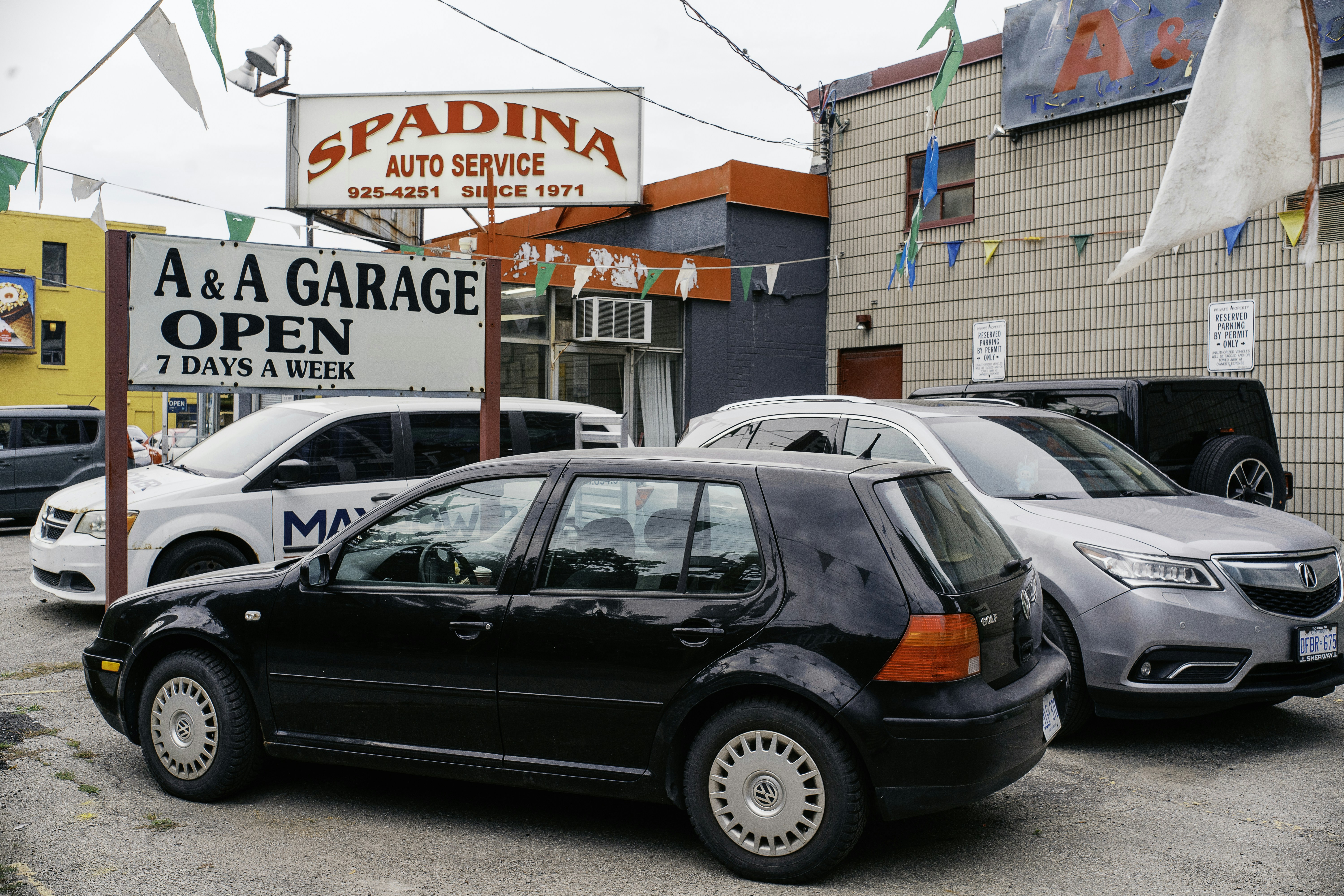 Black hatchback anchored at a busy auto shop lot