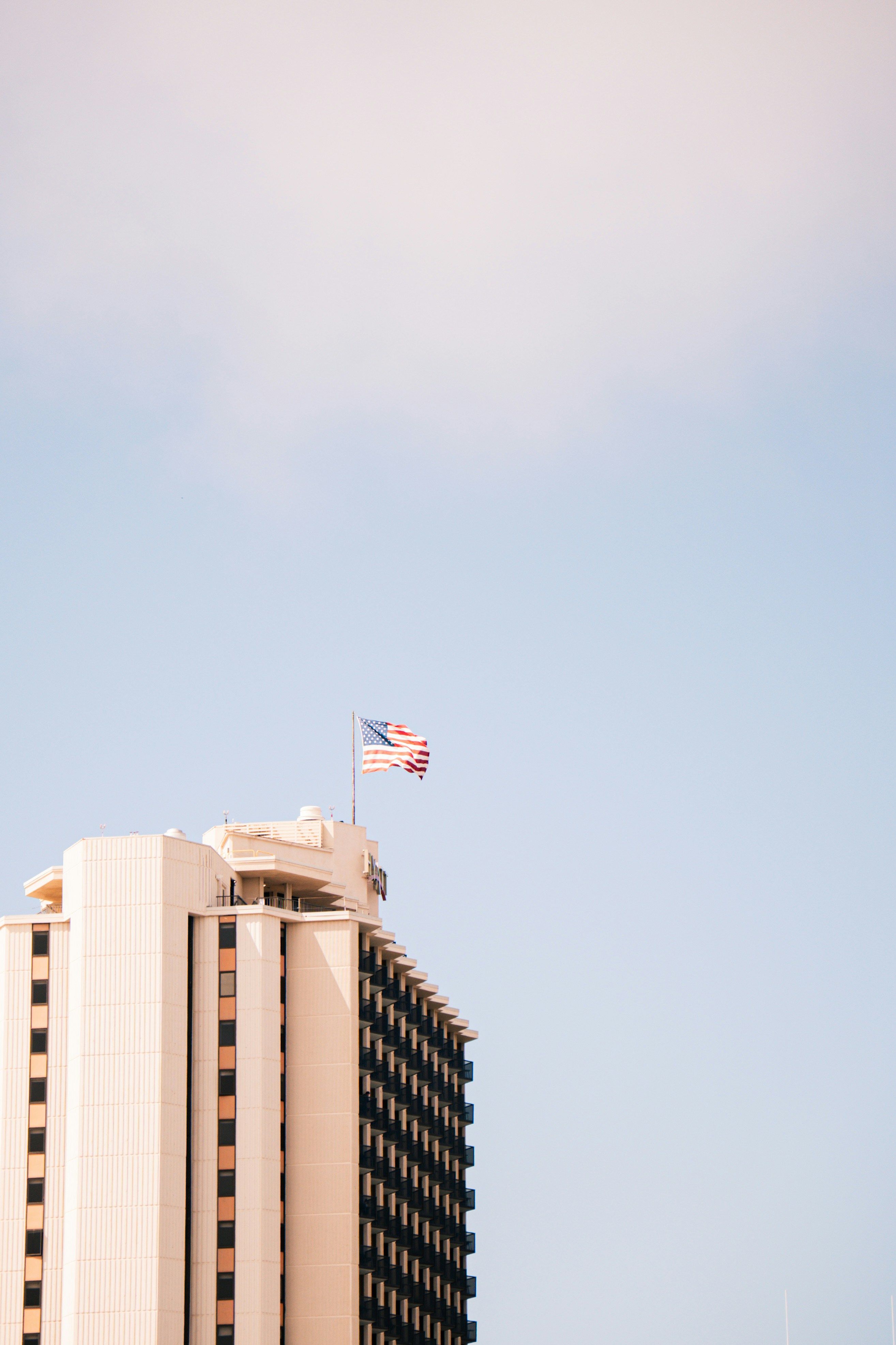 Flag atop the skyline: American banner against a pale sky
