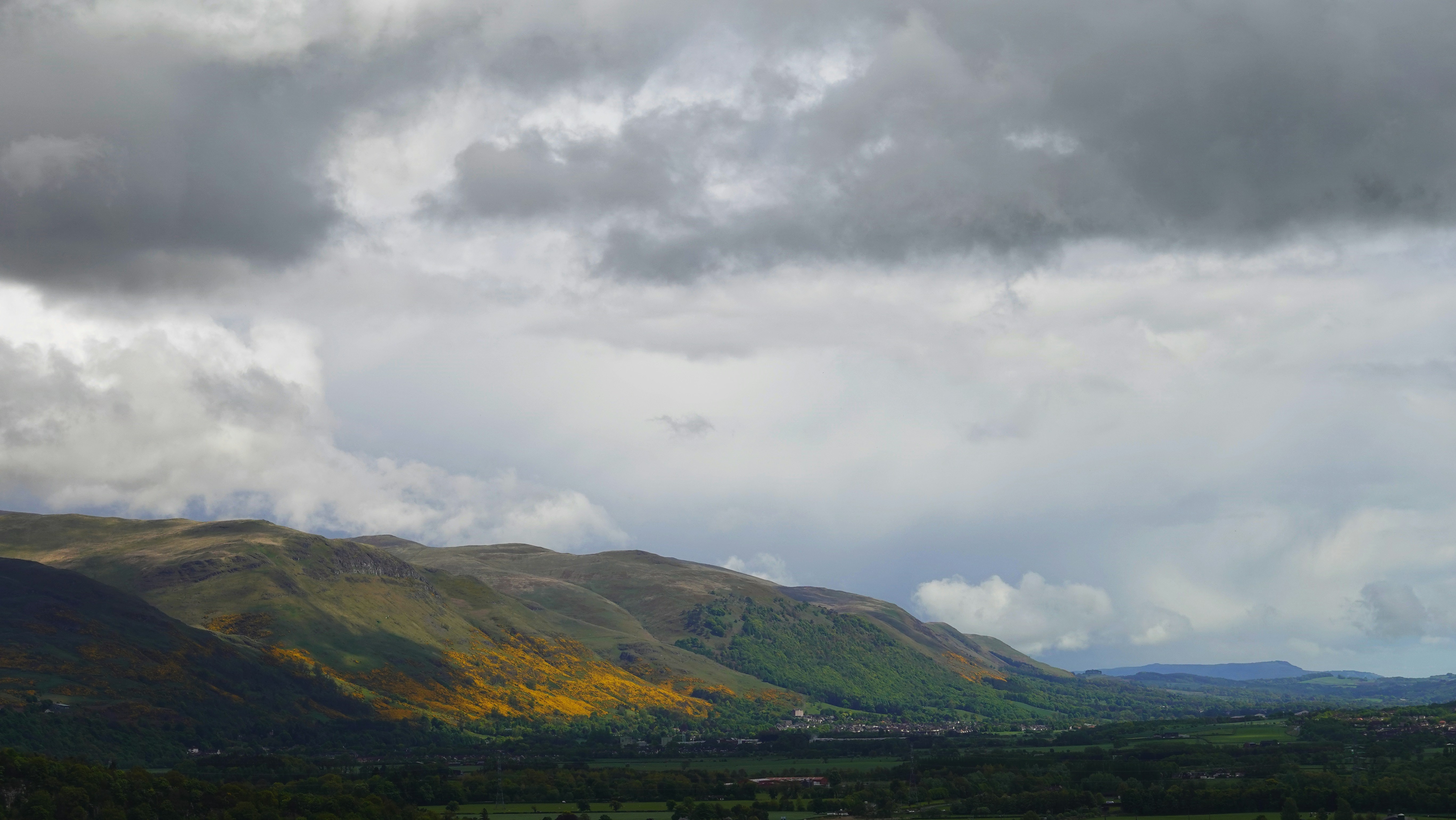 Sunlit Ridge: A Quiet Valley Under sweeping Clouds