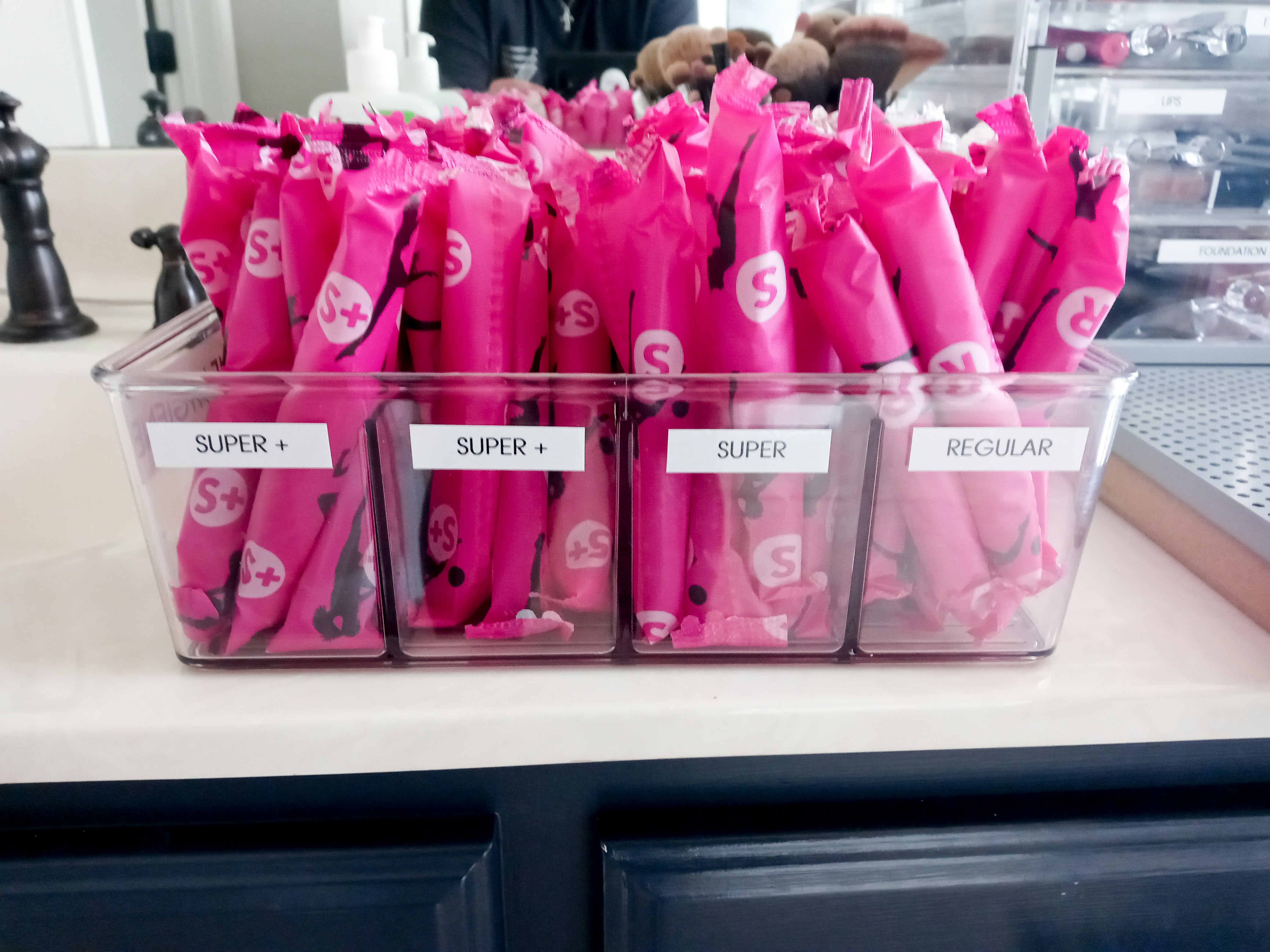 Colorful pink packaging arranged in clear bins labeled SUPER+ and REGULAR on a store counter.