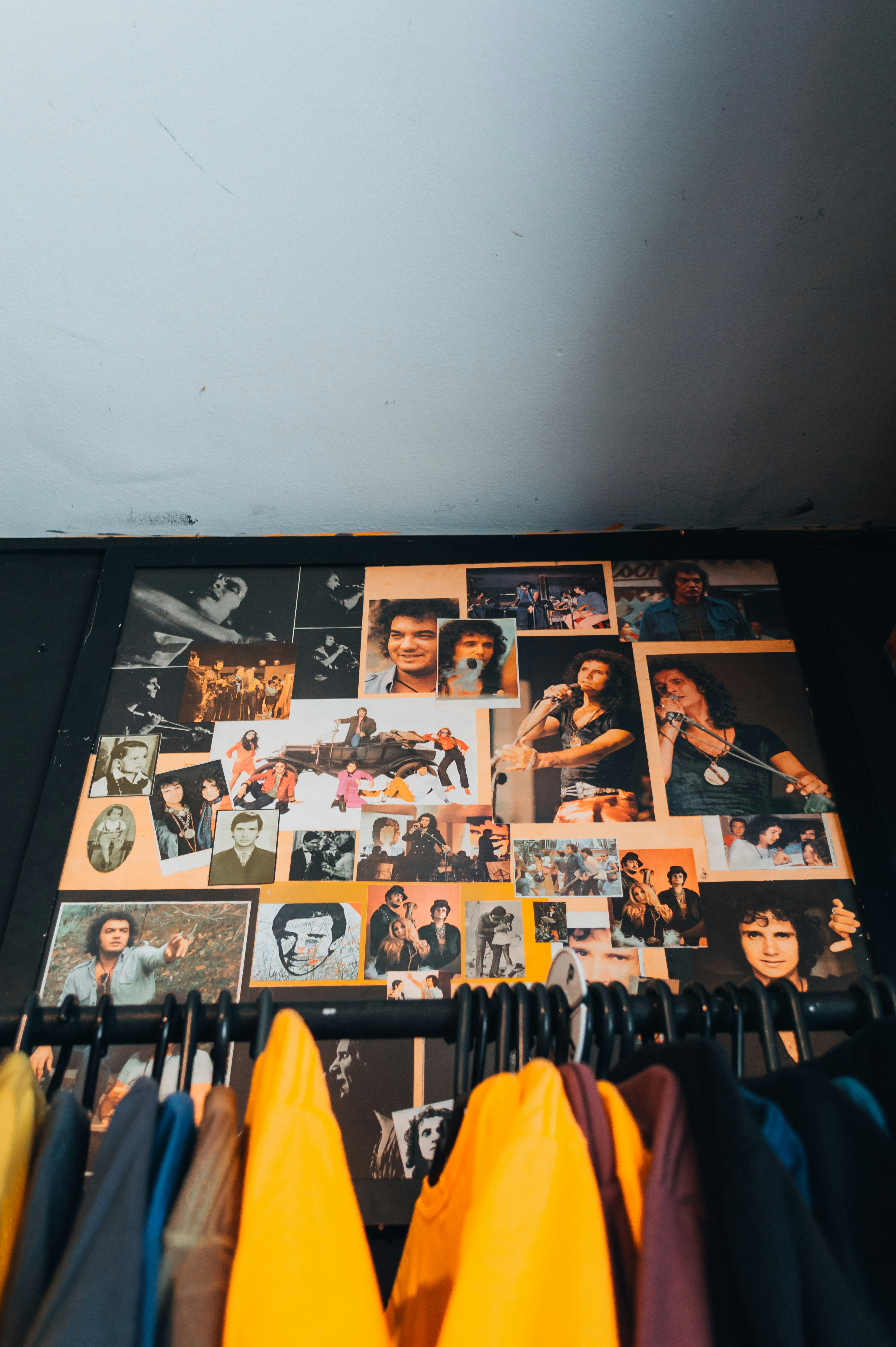 A Wall of Iconic Portraits Above a Trolley of Colorful Coats