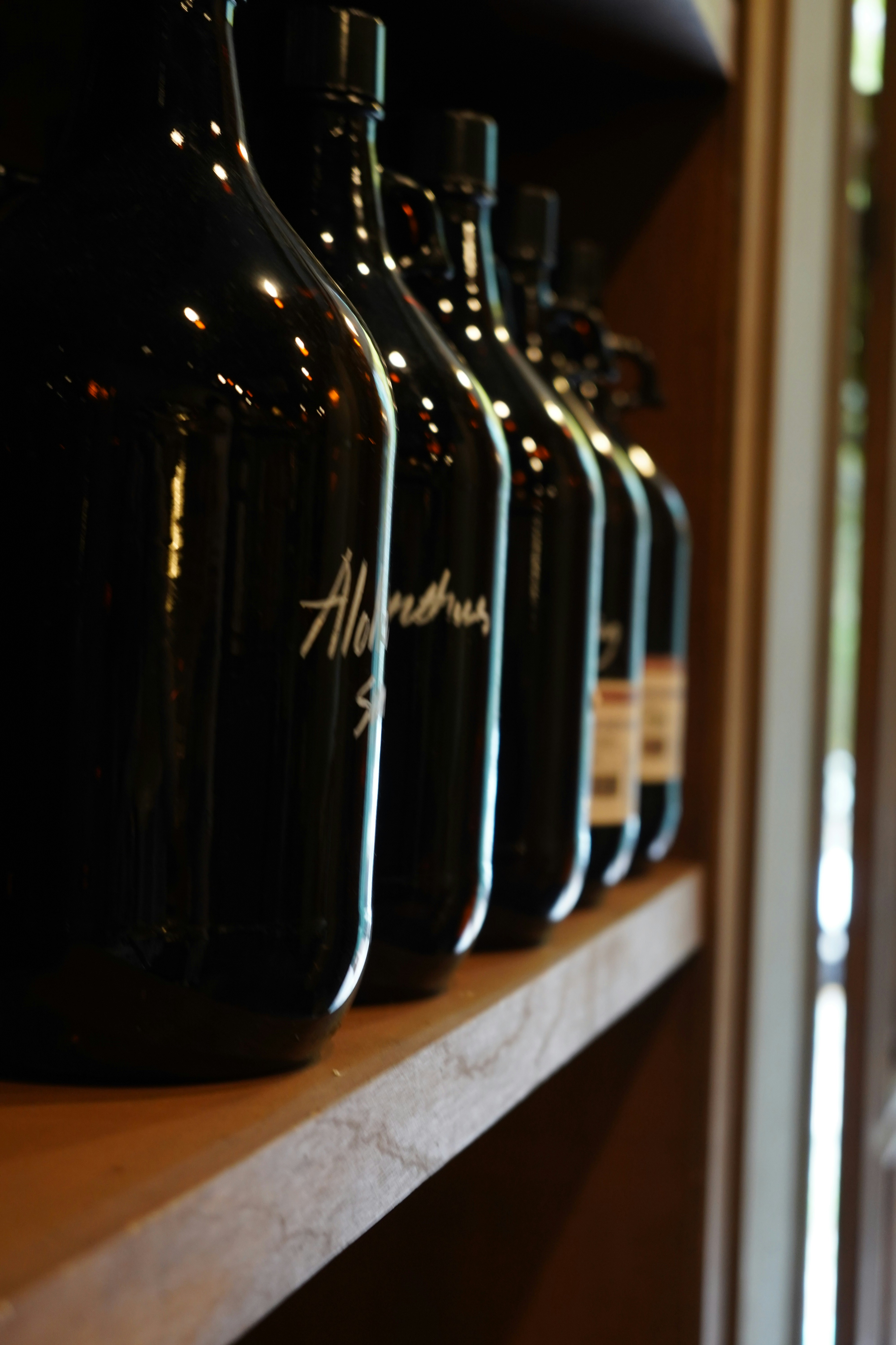 Row of Dark Glass Bottles on Wooden Shelf