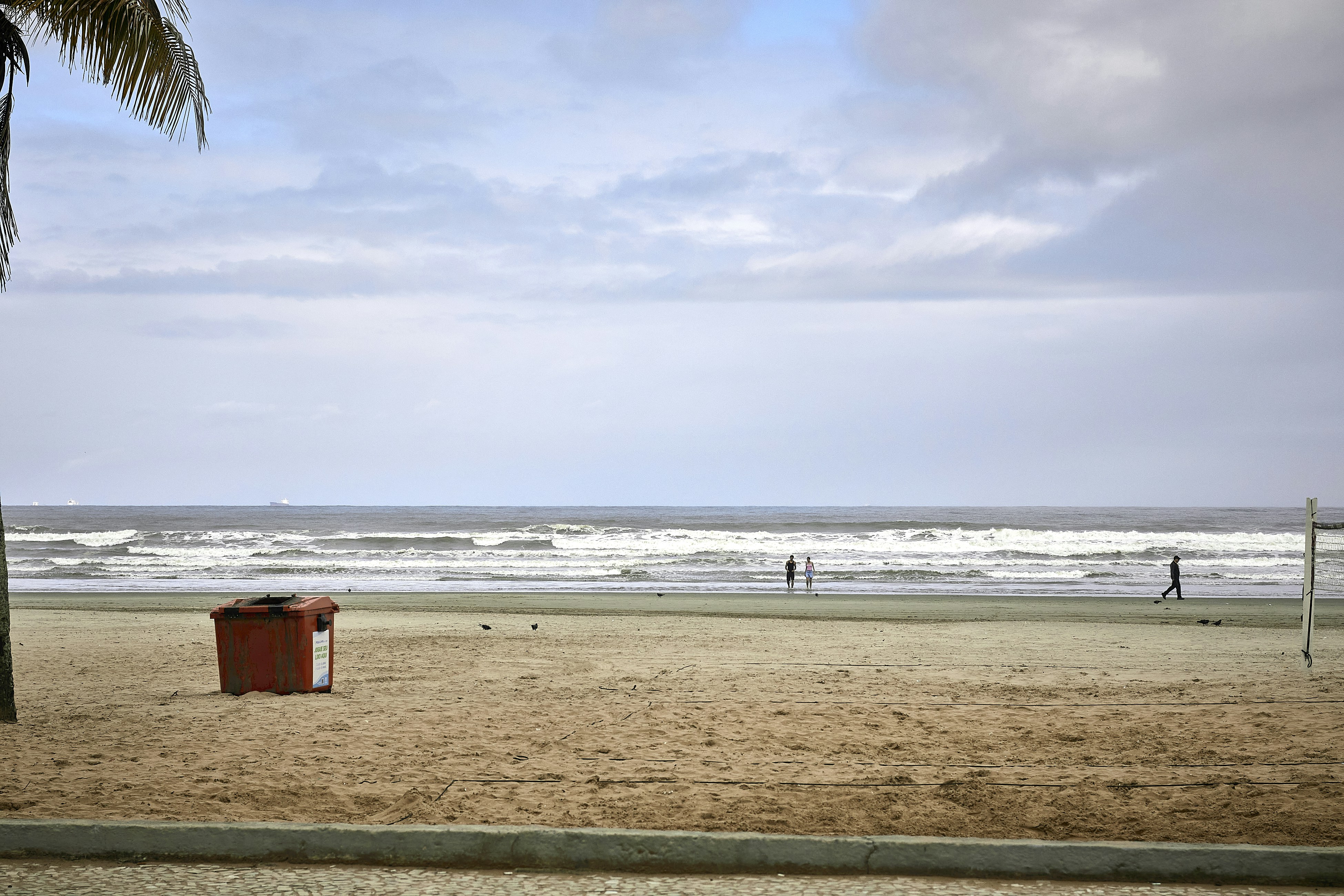Lonely Red Bin and Distant Waves: Quiet Beach at Midday