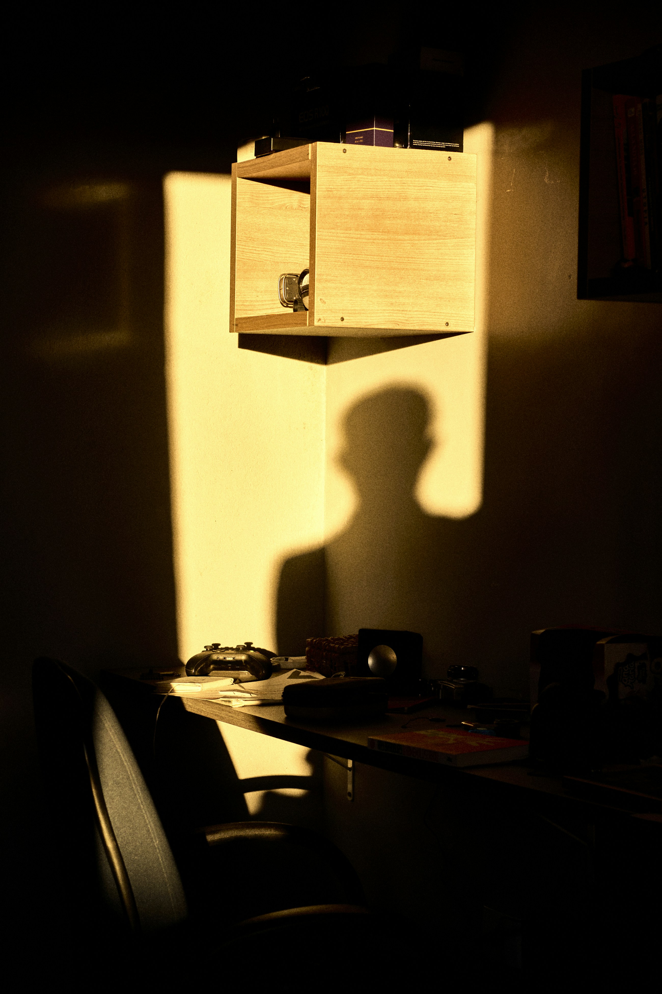 Shadowed Workspace: A Hanging Shelf Casts a Golden Silhouette