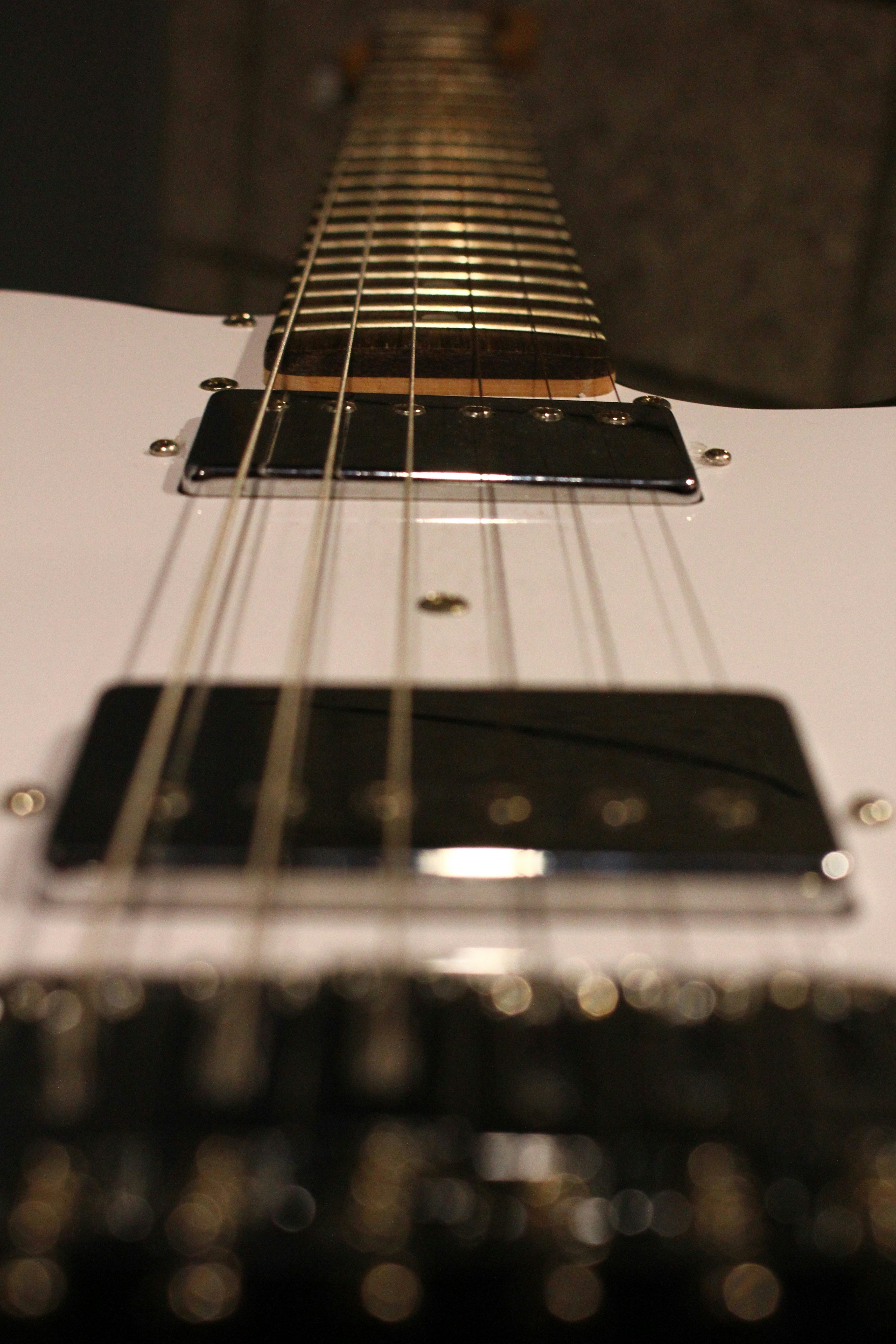 Strings in Focus: A Close-Up Down the Neck of a White Electric Guitar