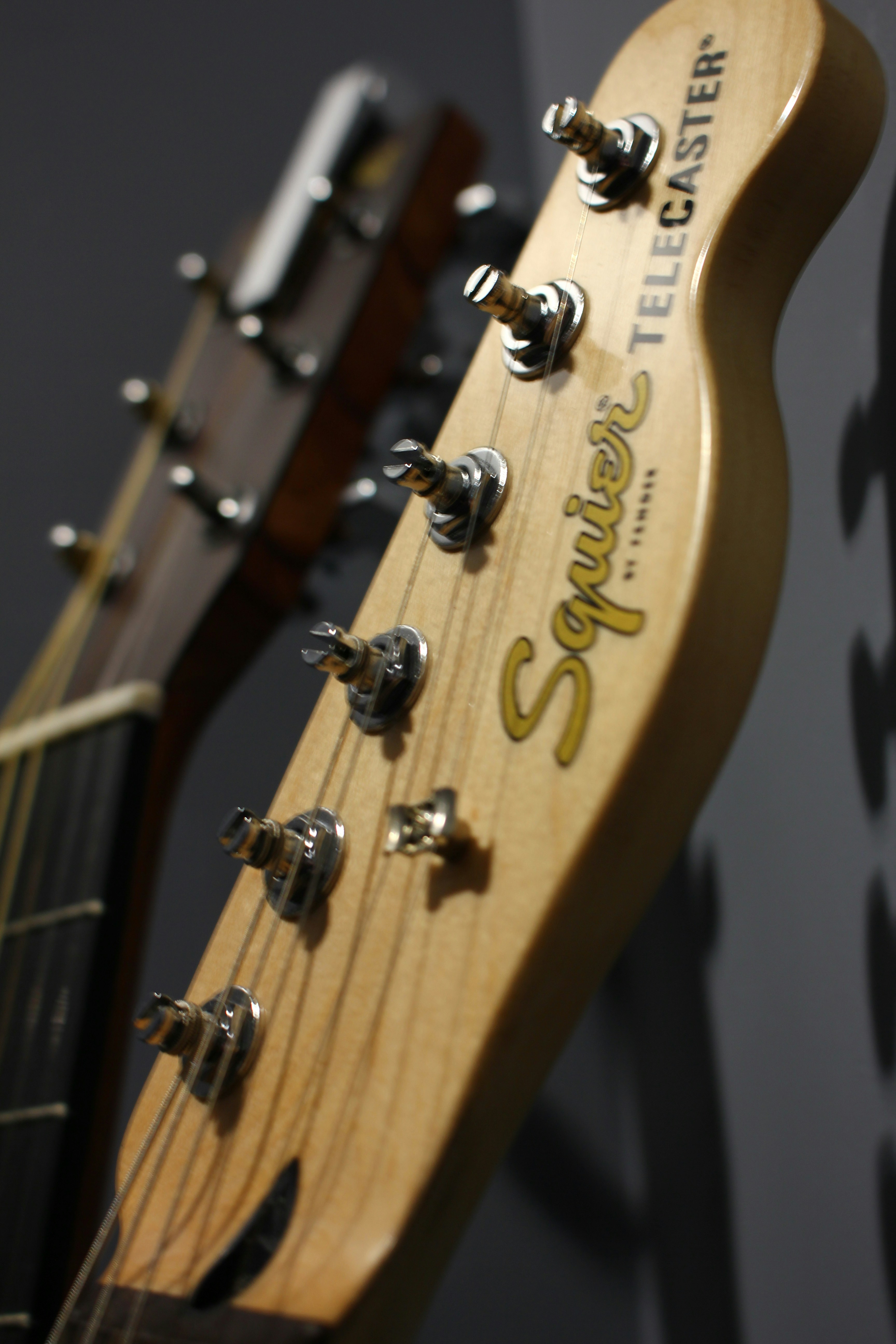 Close-up of a guitar headstock: vintage Fender-like logo in soft light