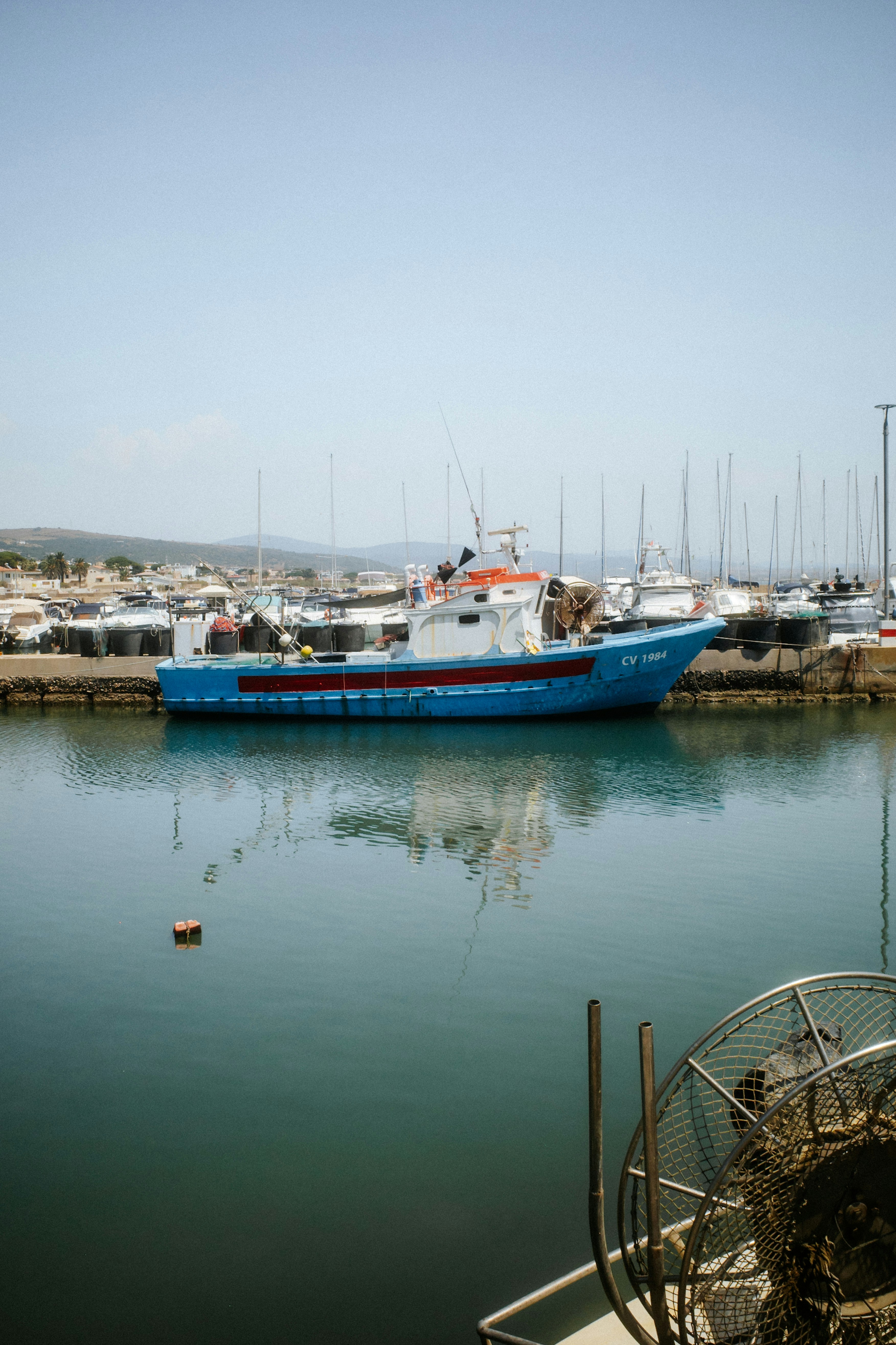 Blue-hulled Workboat Anchored in a Calm Marina