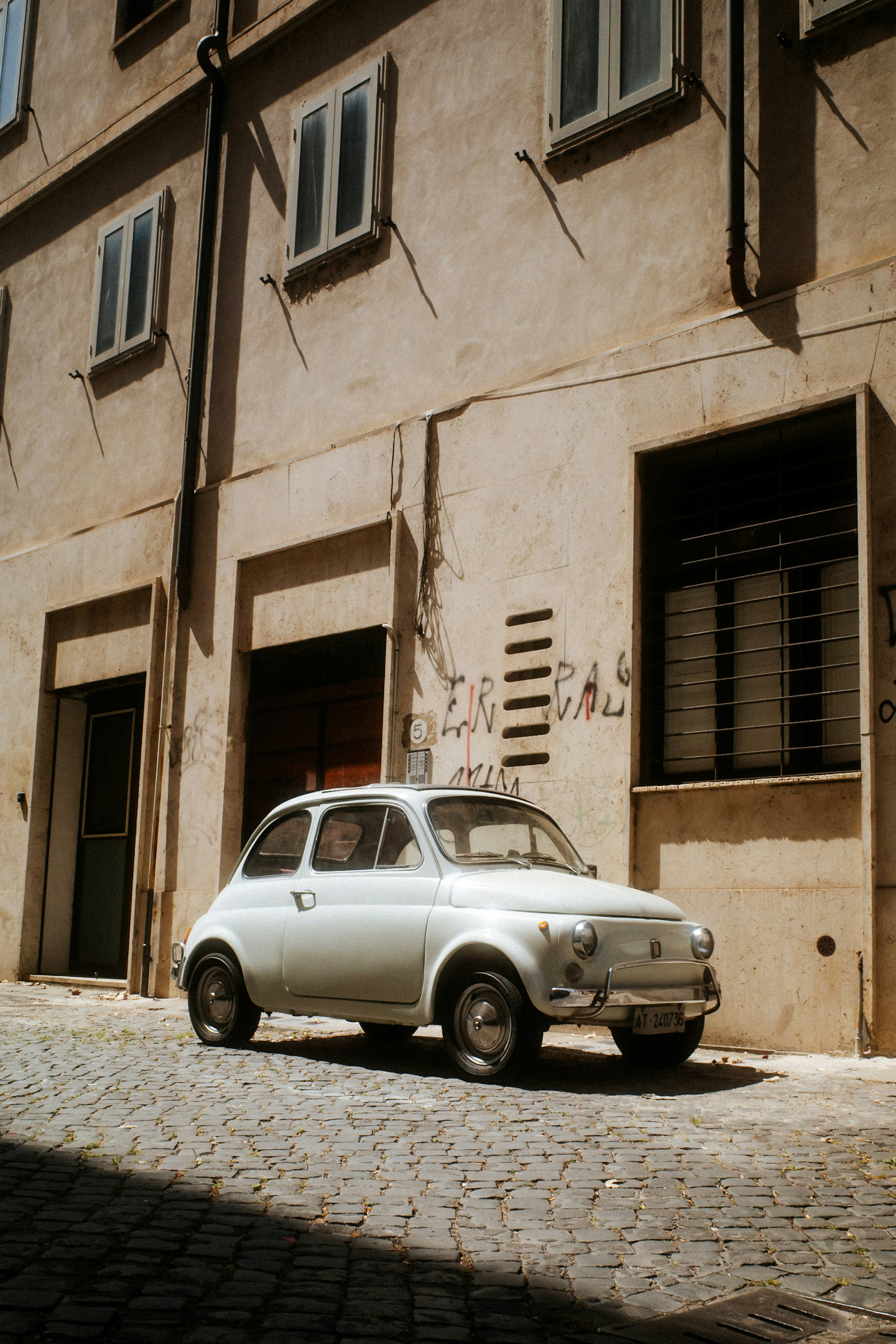 Vintage Fiat on a Sunlit Cobblestone Street