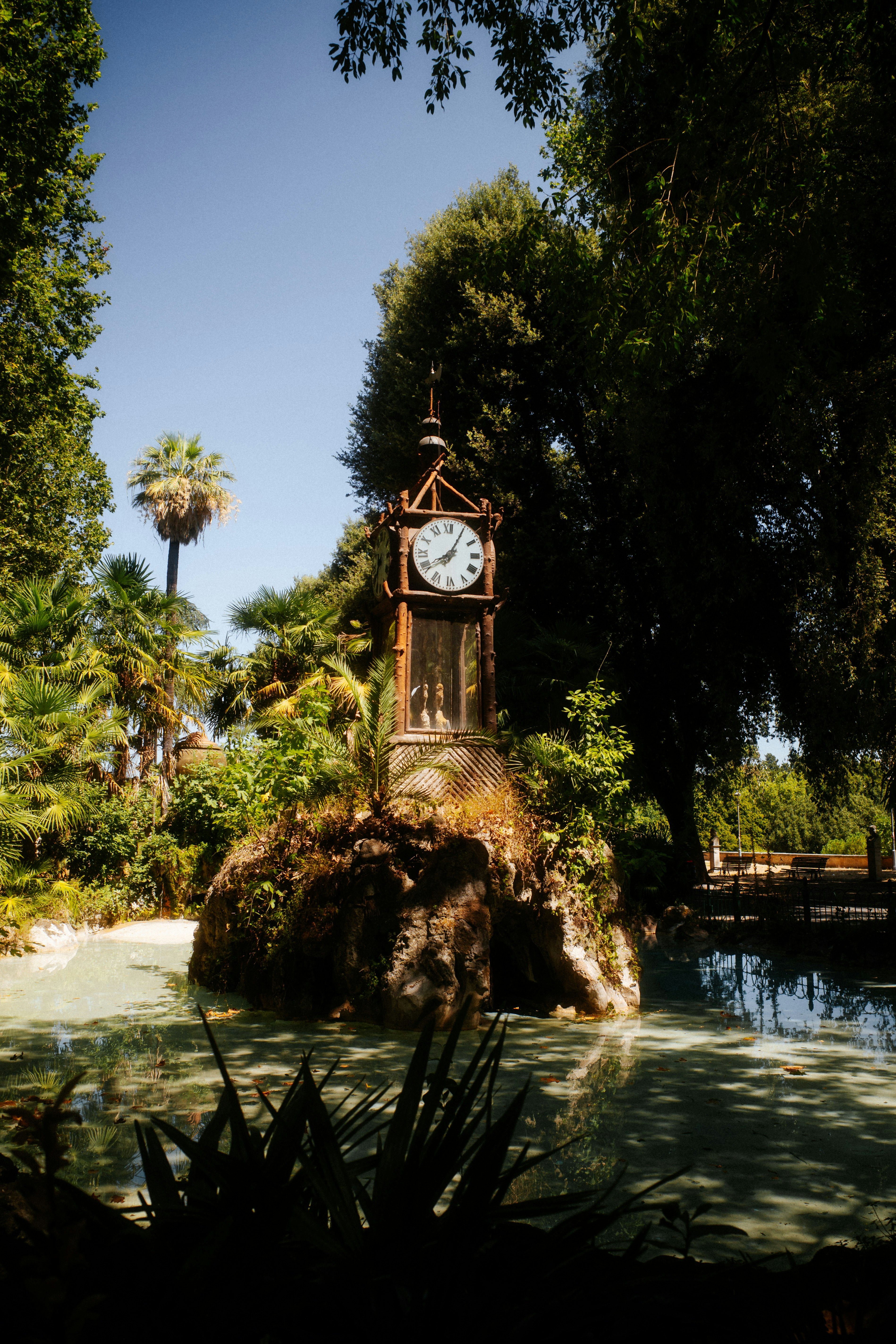 Rustic clocktower on a rocky island amid a lush garden