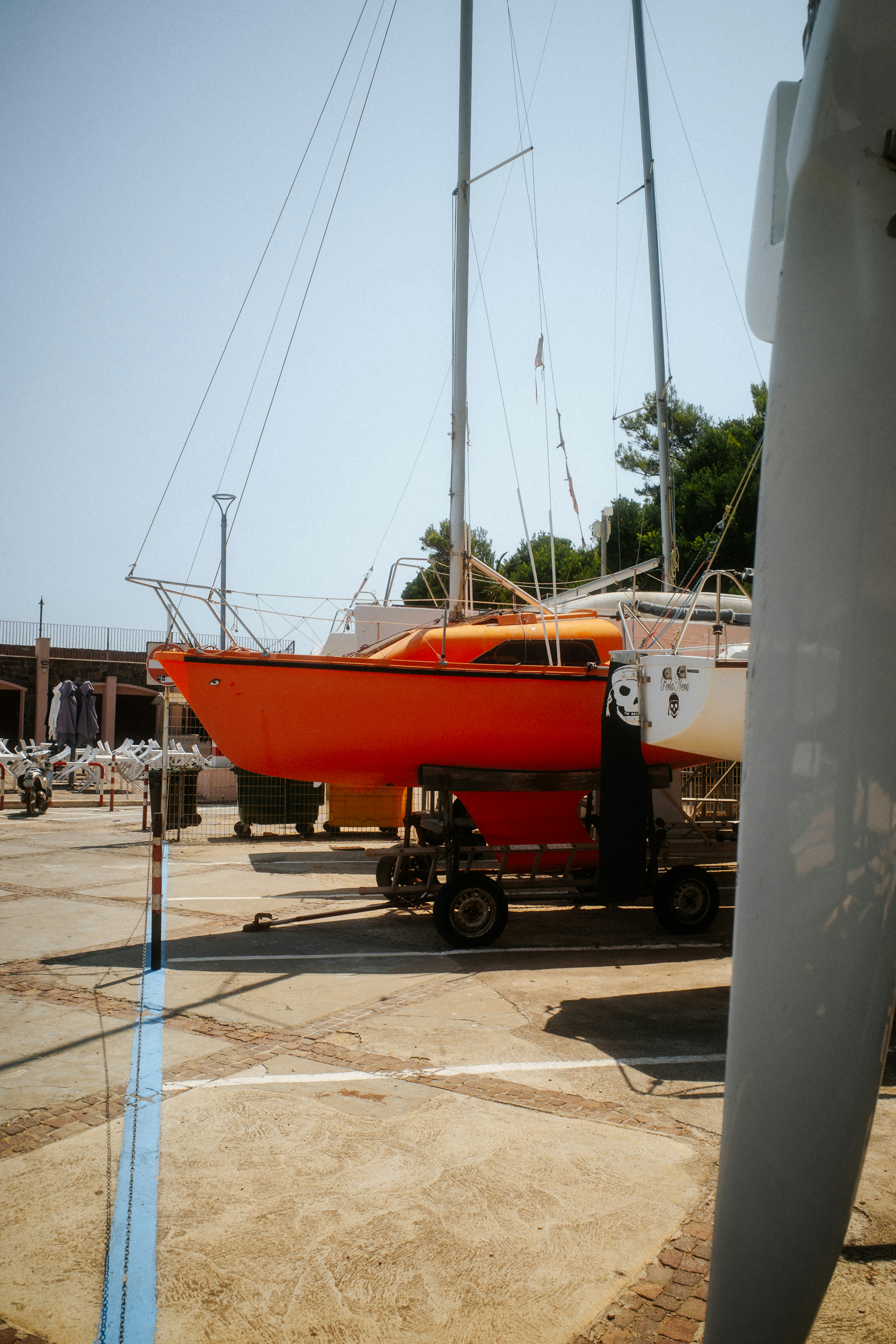 Orange Sails in the Marina: Boatyard Quiet Under Blue Sky