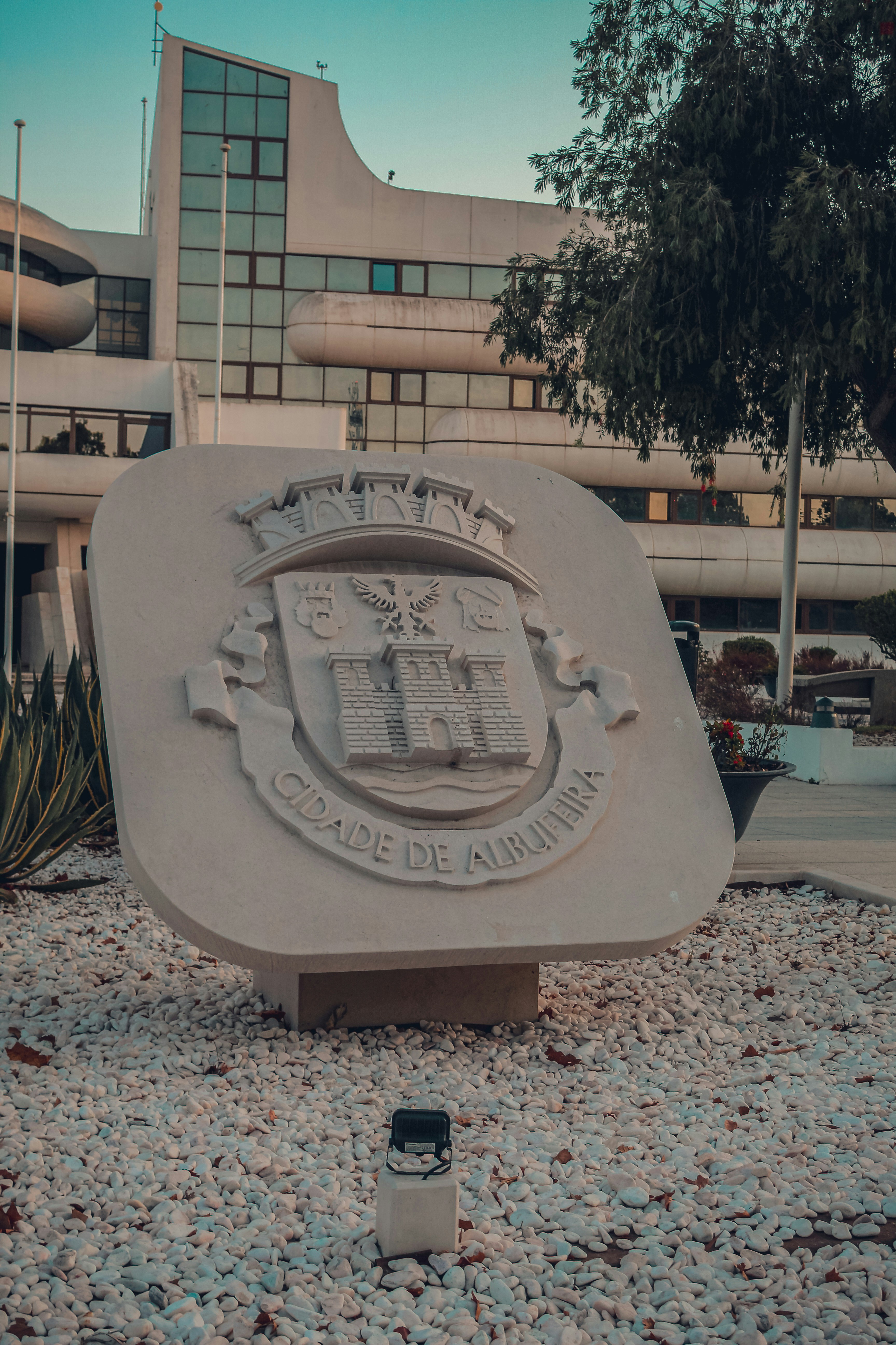 Emblem at the Center: A Civic Stone Monument Framed by Modern Architecture