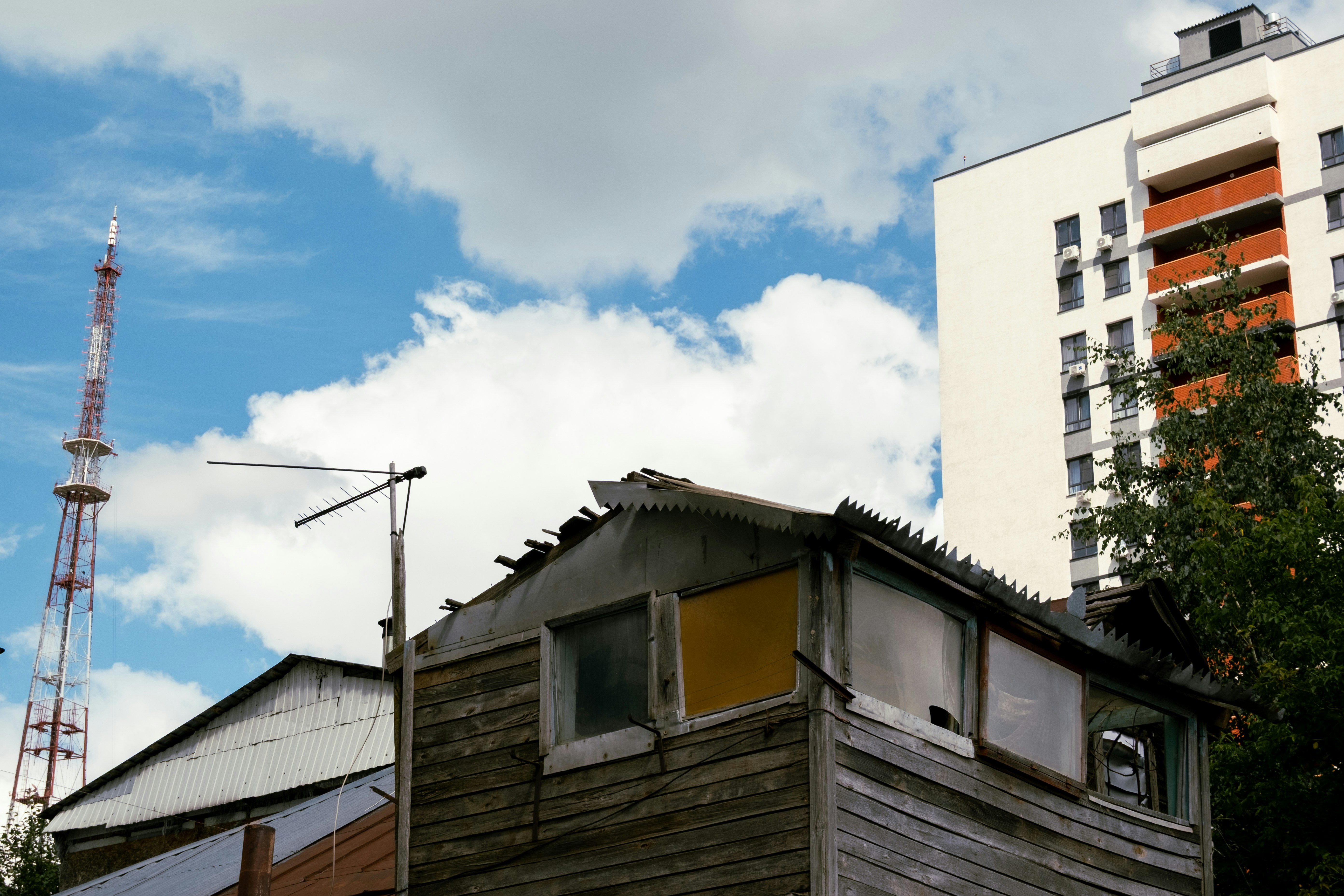 Weathered shack meets modern high rise under a bright sky