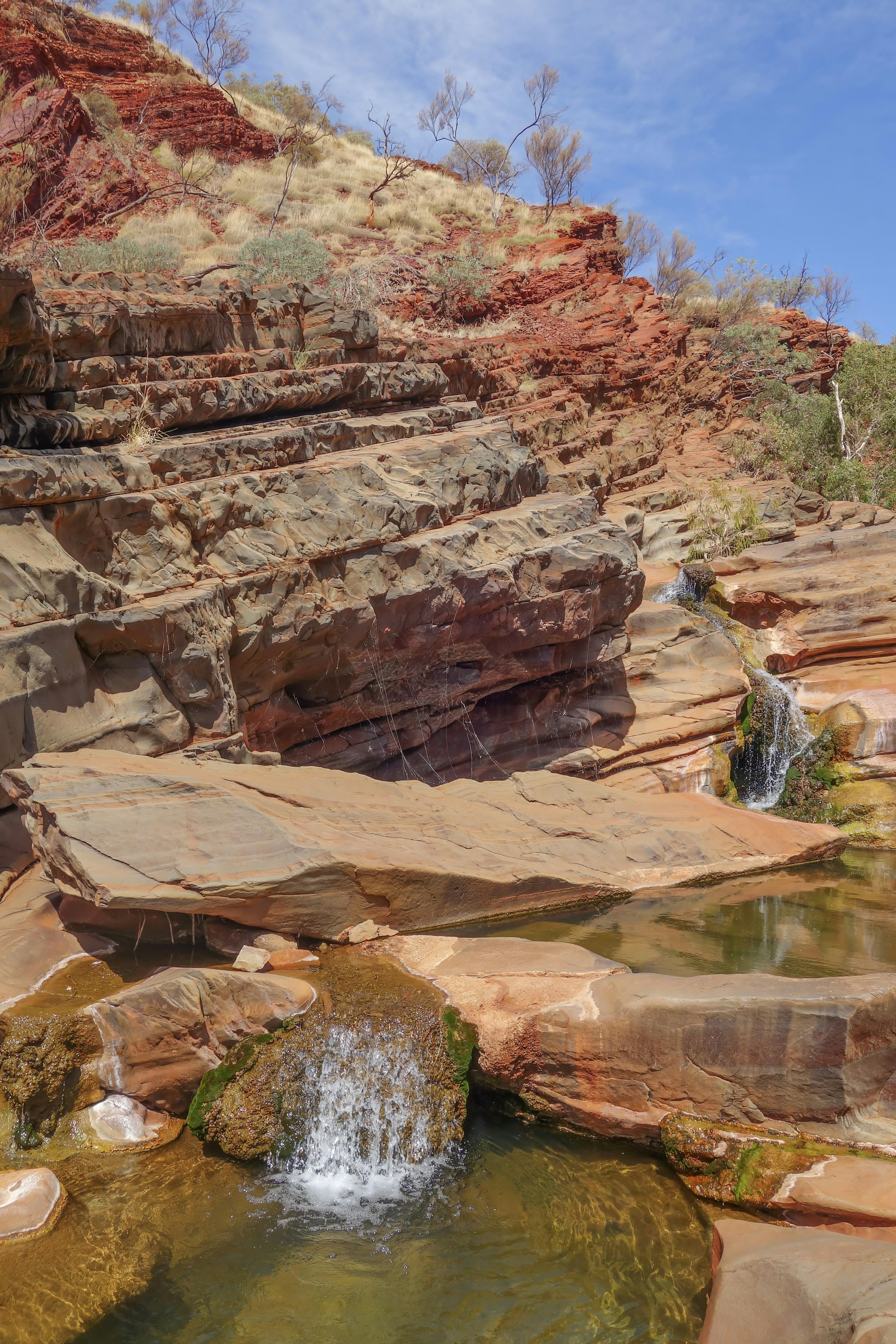 Red Rock Cascade: Sculpted terraces and a tiny waterfall in ochre light