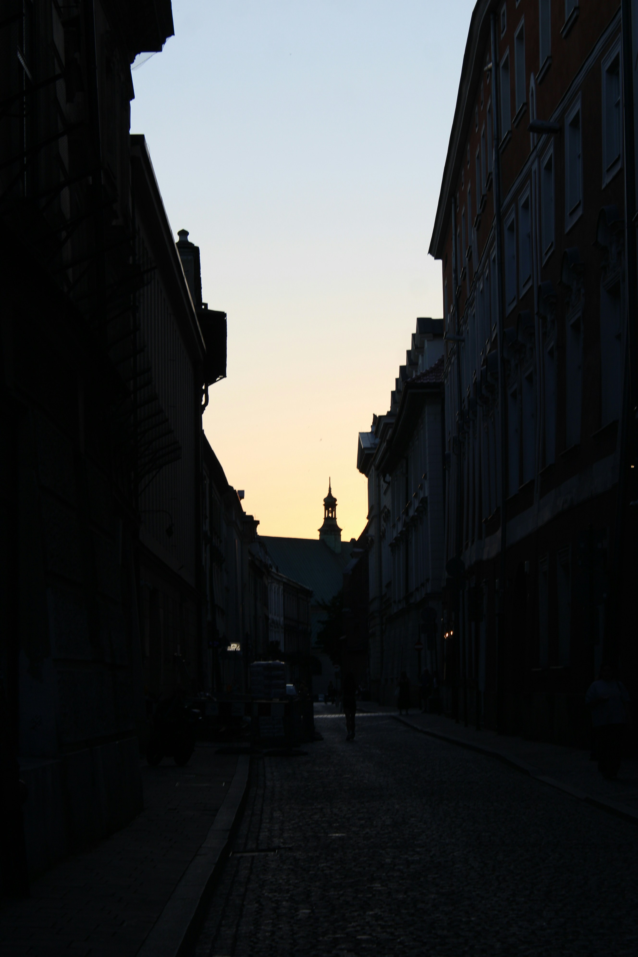 Dusk in the Narrow Canyon: A Quiet Street Framed by Silhouettes