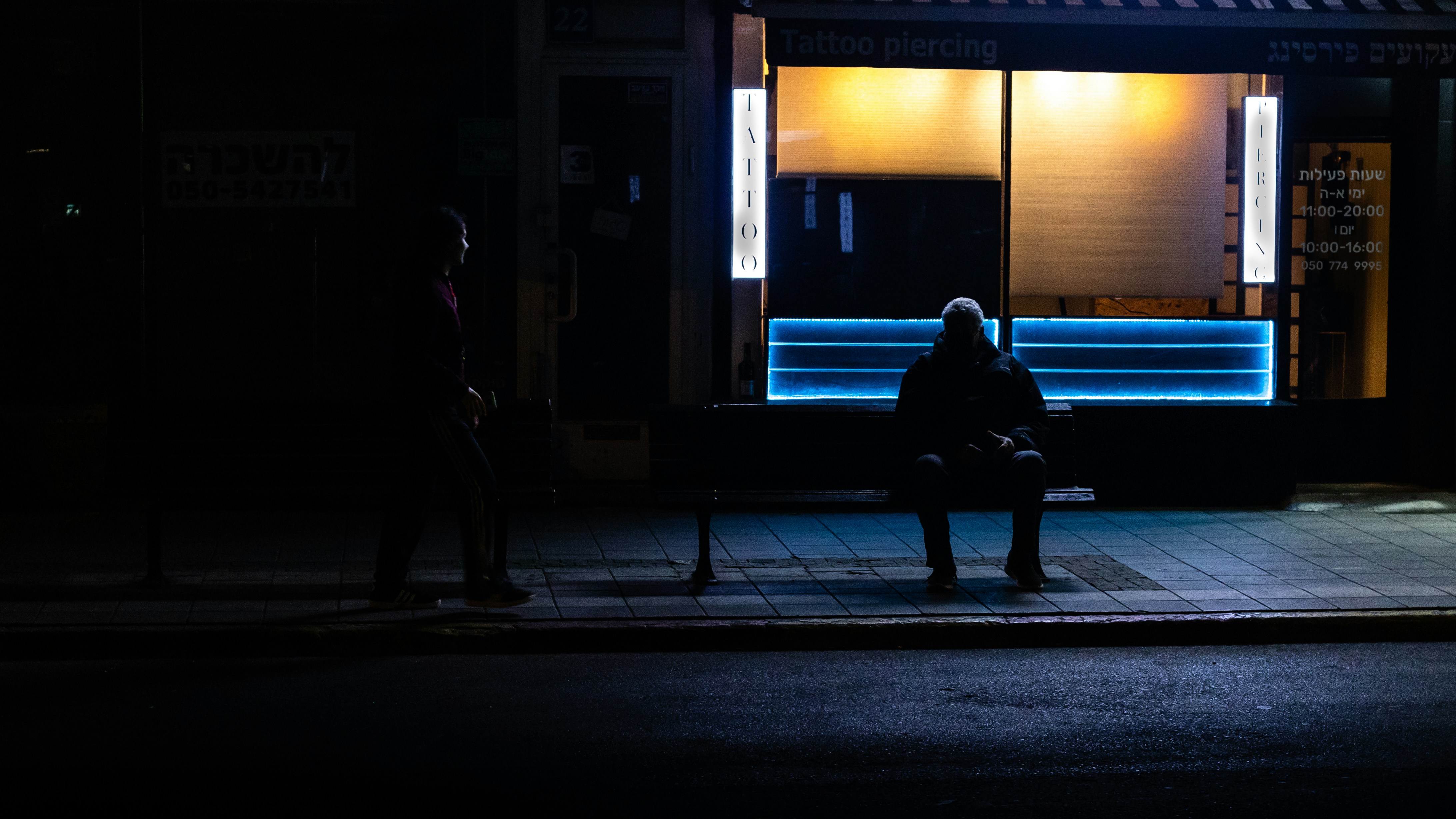 Neon Quiet: A Seated Figure Under Blue Glow
