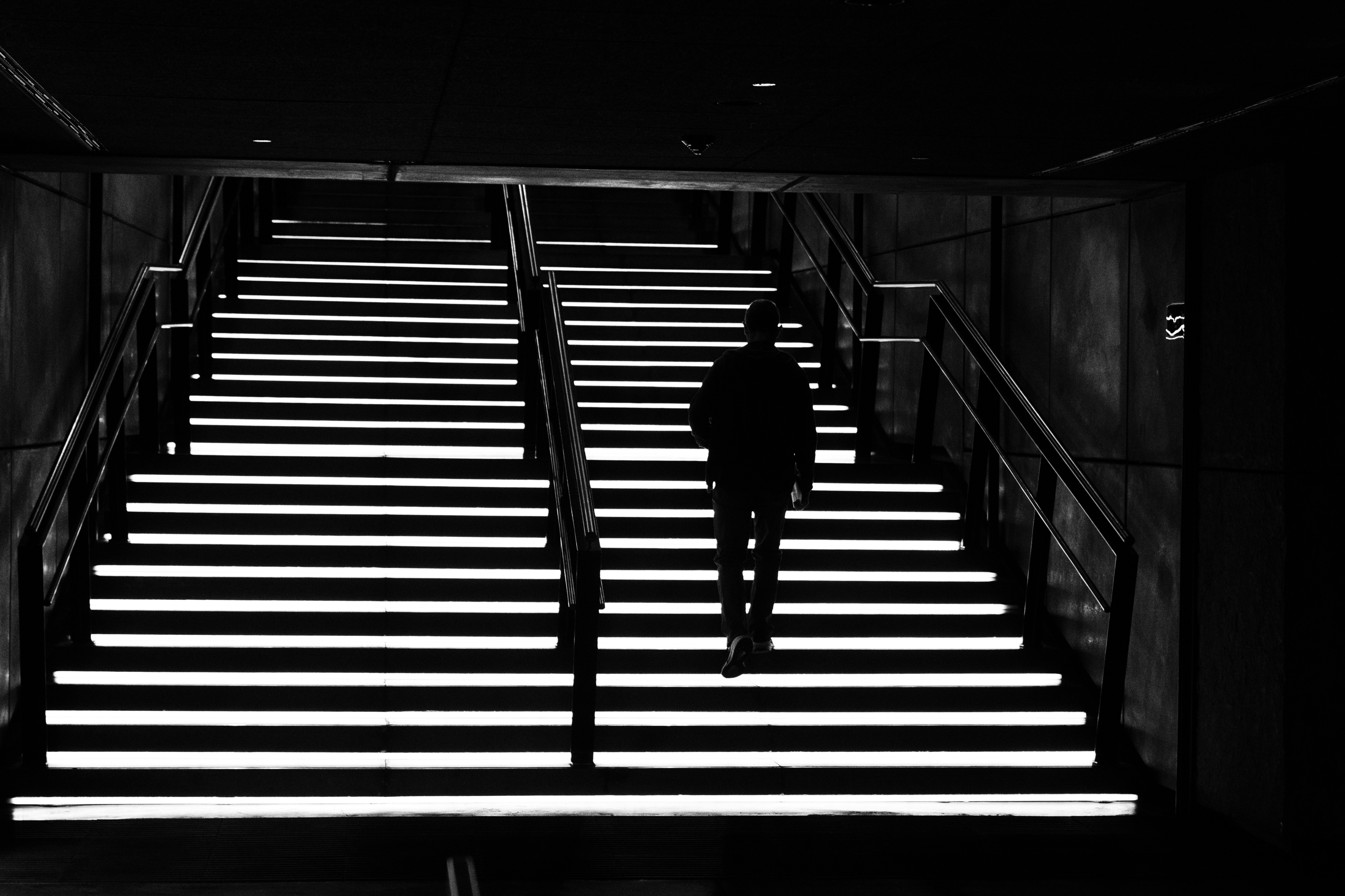 Silhouette Ascent: A lone figure up the glowing stairs