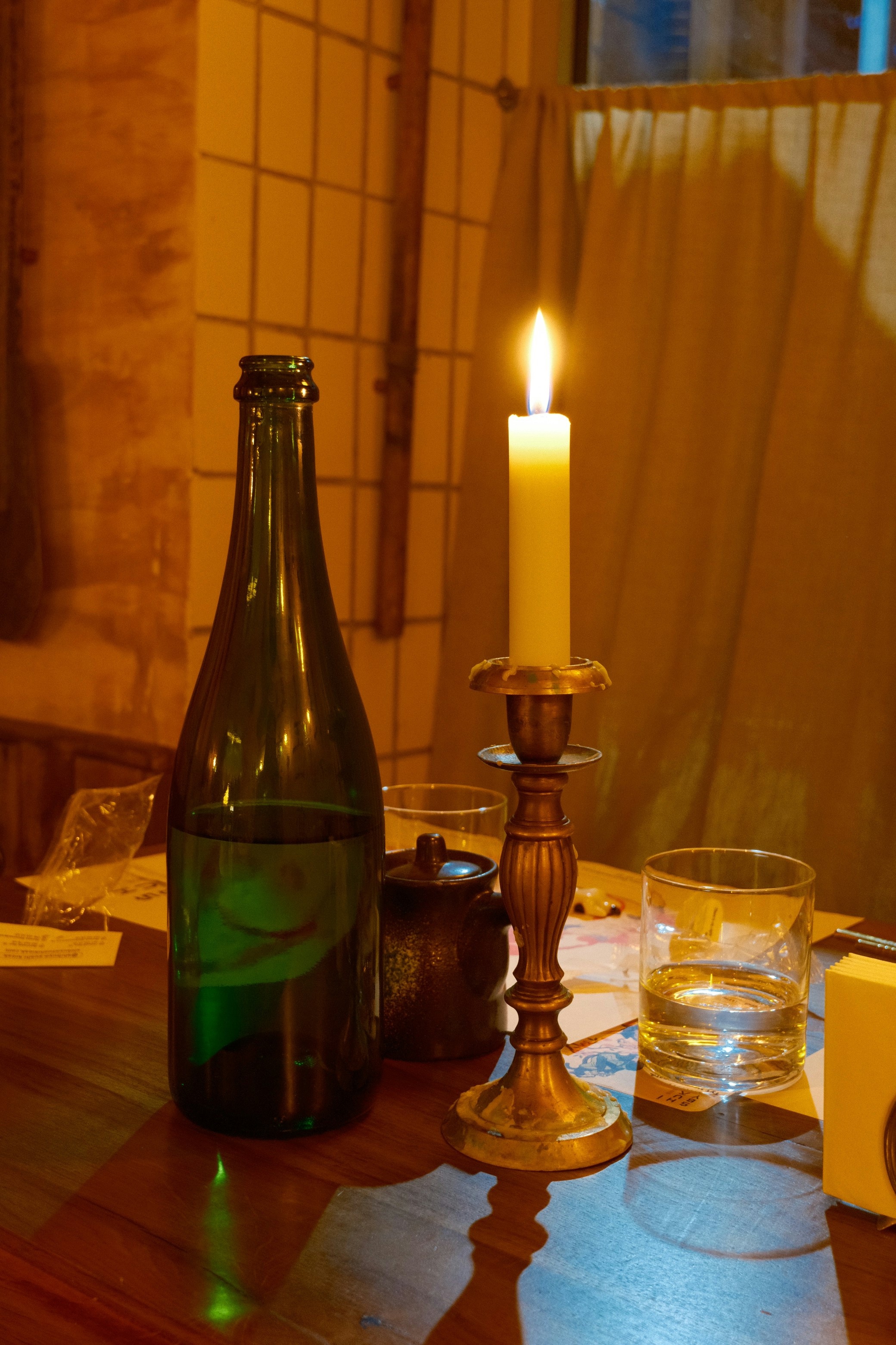 Candlelit Still-Life: Bottle, Glass, and Dull Curtain Glow