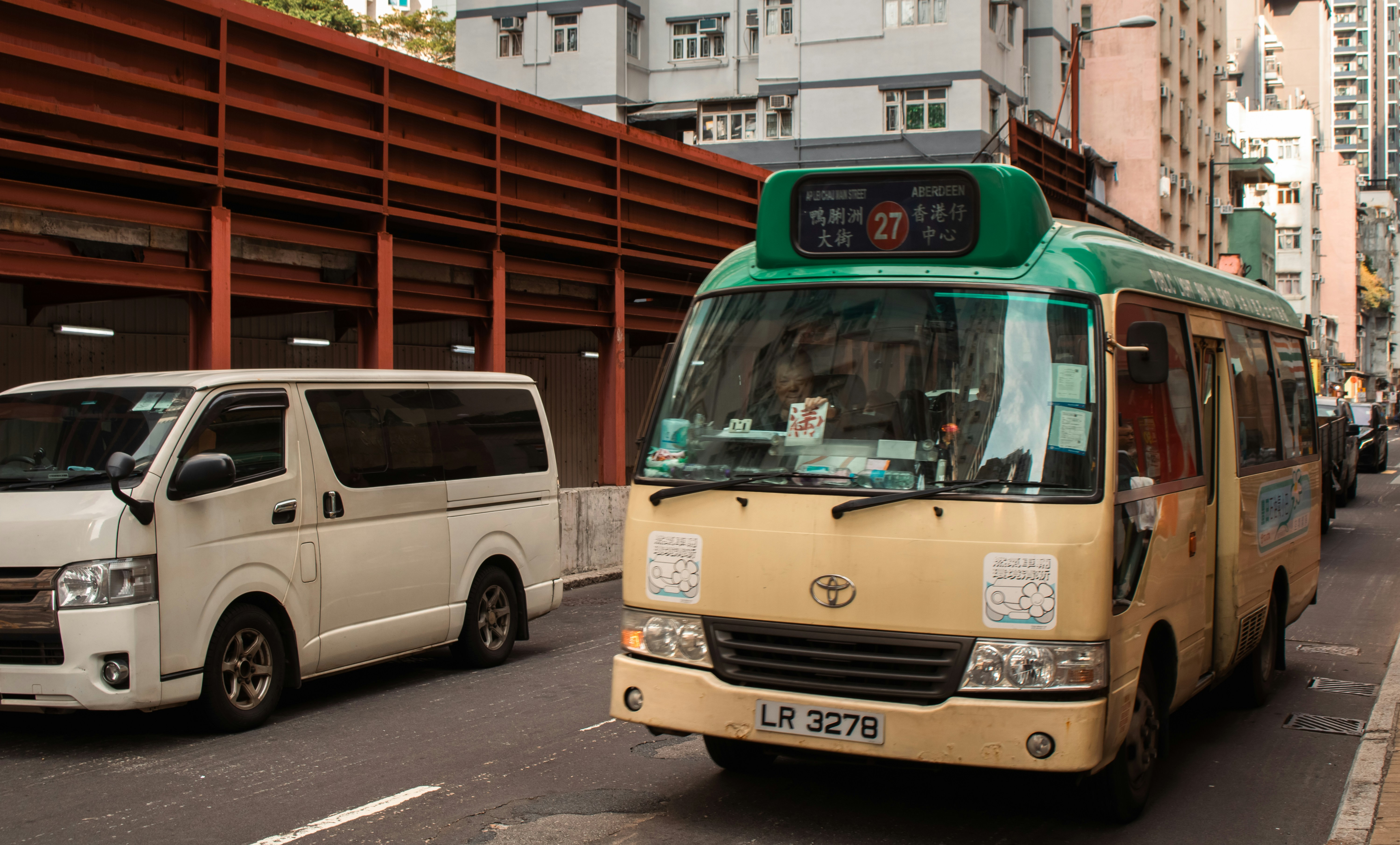 Bus on a crowded city street with a beige van in the foreground