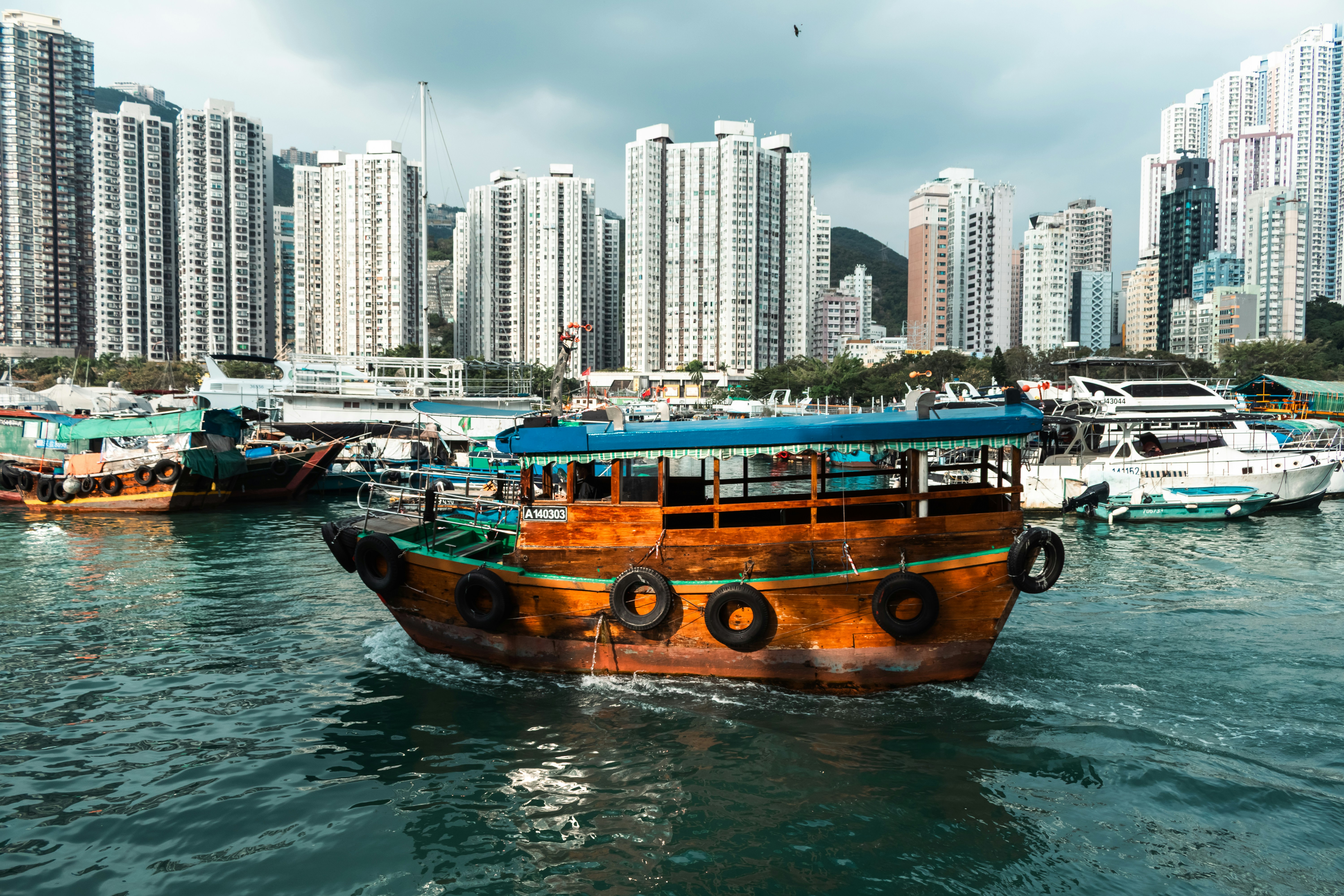 Harbor of Giants: A Traditional Boat Anchored Before a City of Glass